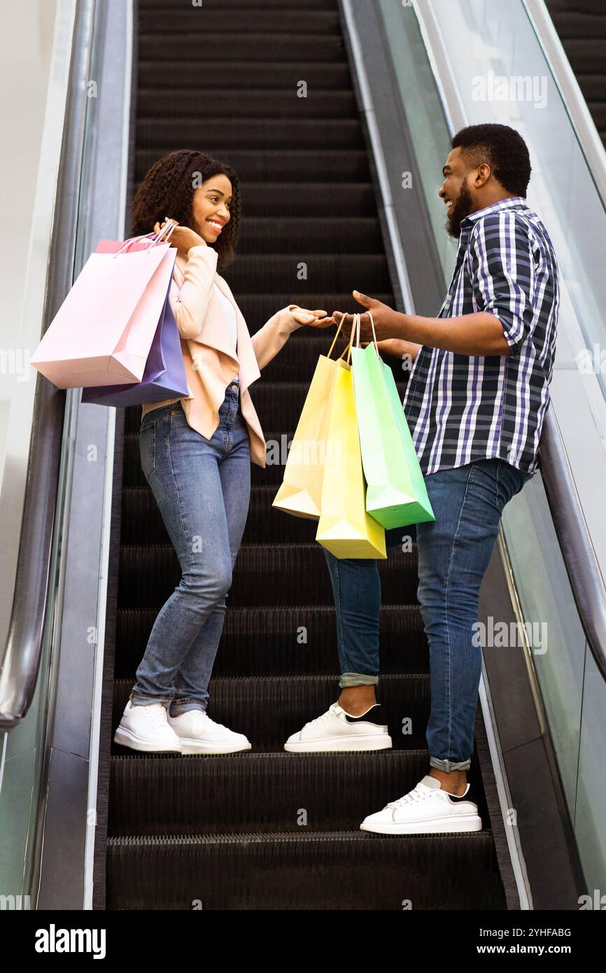 Black millennial couple spending time in shopping mall, going up the ...