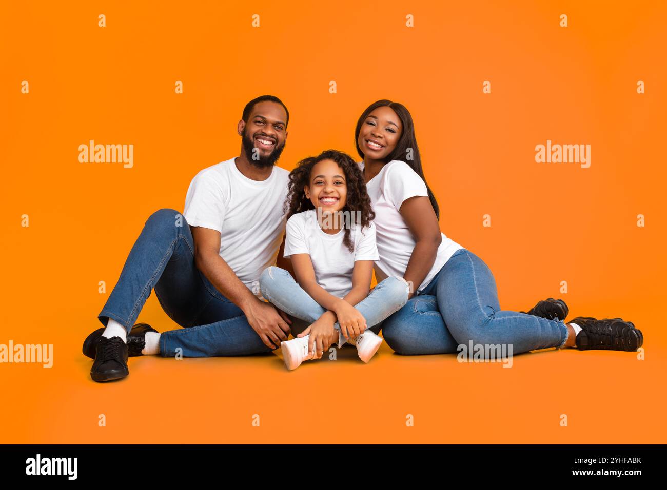 Black guy hugging smiling lady and girl, sitting on floor Stock Photo ...