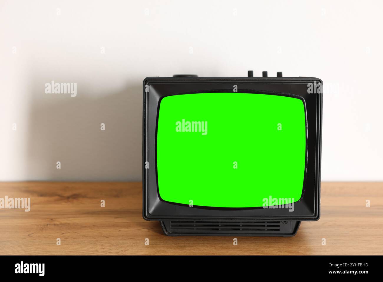 Retro Tv set with green screen on wooden table near white wall, space ...