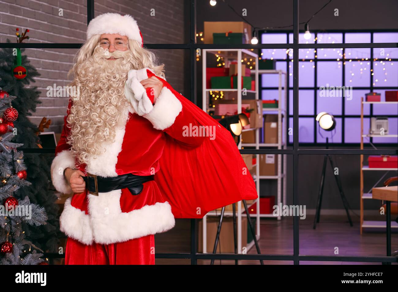Santa Claus holding bag of gifts in post office with parcels and ...
