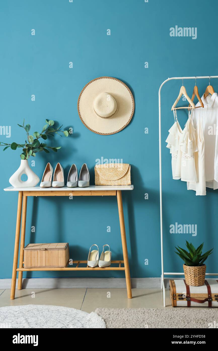 Shoes on table and rack with clothes near blue wall in room Stock Photo ...