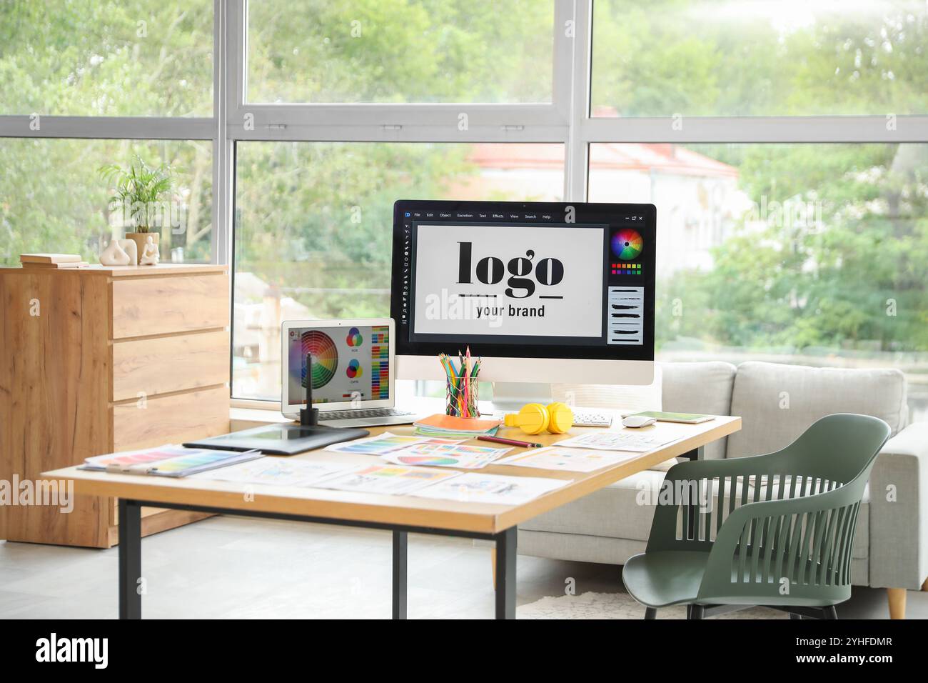 Graphic designer's workplace with computer, laptop and color palettes ...