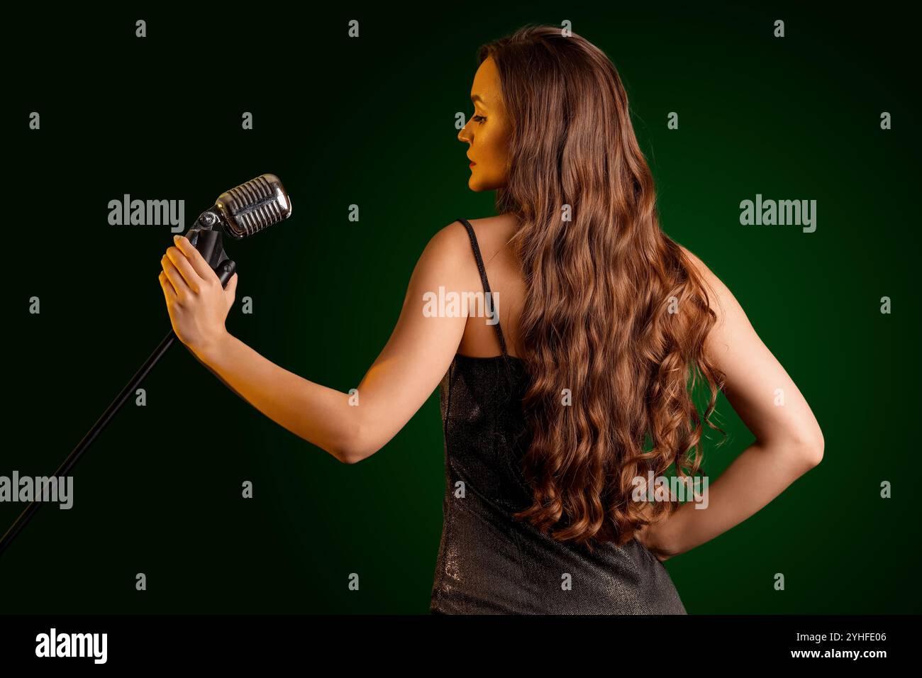Female singer with microphone on dark green background, back view Stock ...