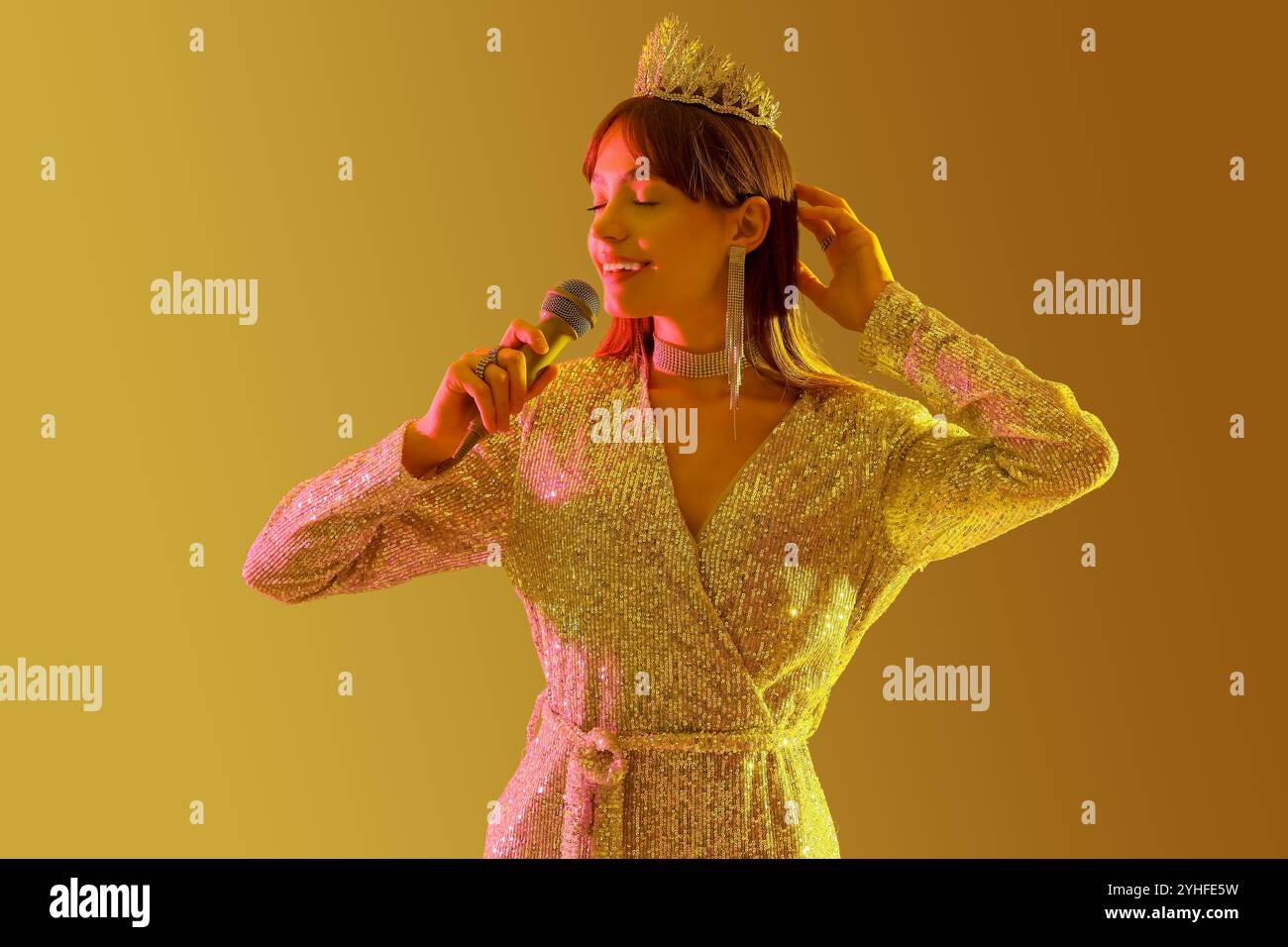 Beautiful singer in tiara with microphone on color background Stock ...