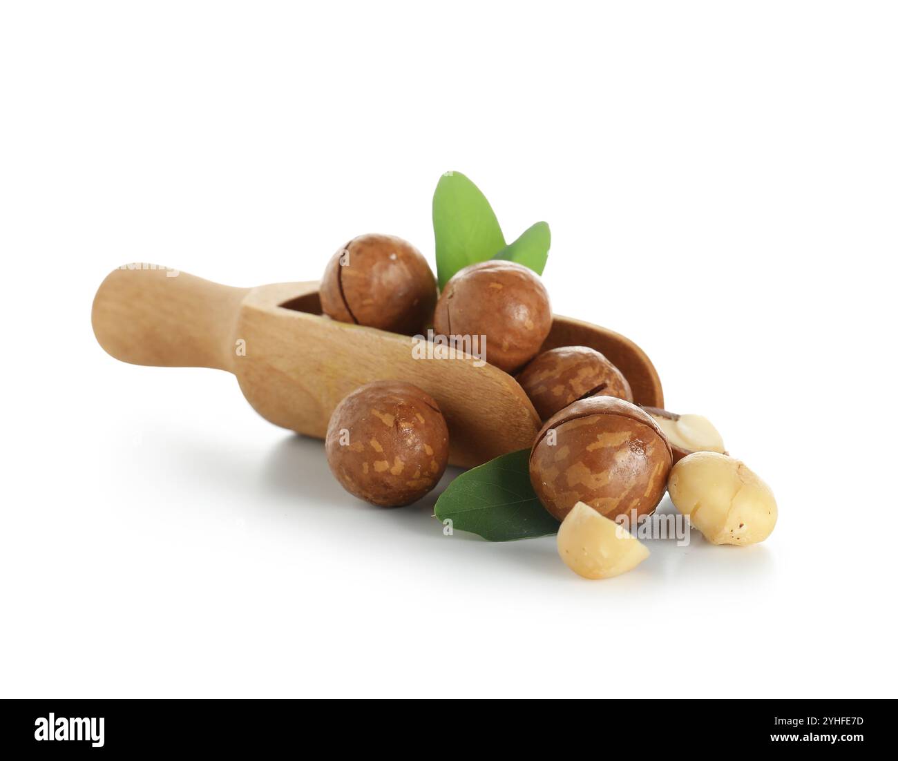 Wooden scoop with tasty macadamia nuts and leaves on white background ...
