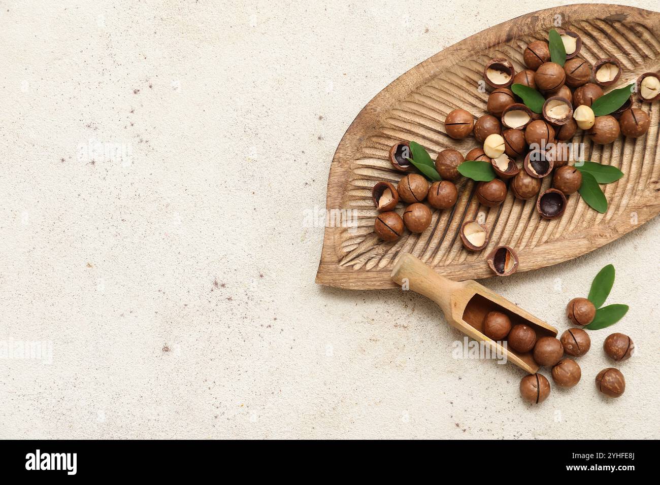Wooden scoop and board with tasty macadamia nuts on white background Stock Photo - Alamy