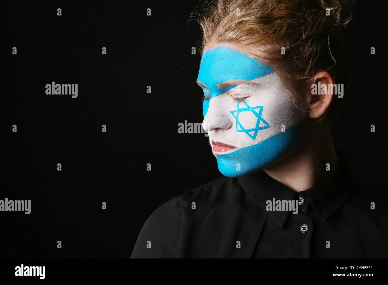 Young woman with painted flag of Israel on her face against black ...