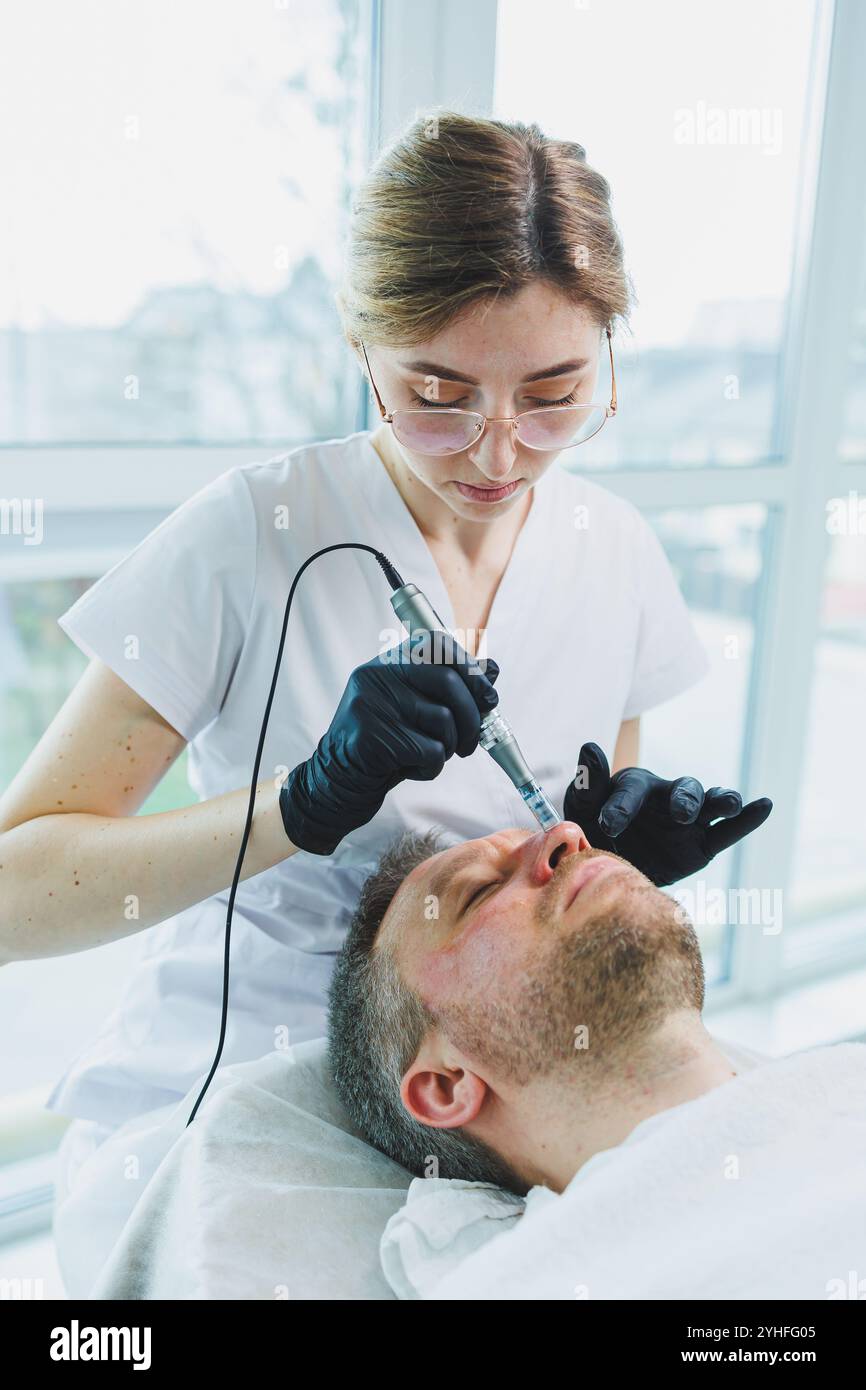 A beautician makes a mask on the face of a man with a beard. Male ...