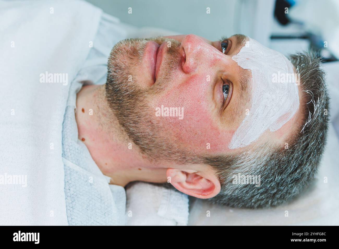 A cosmetologist cleans the skin of a man's face. A man does facial ...