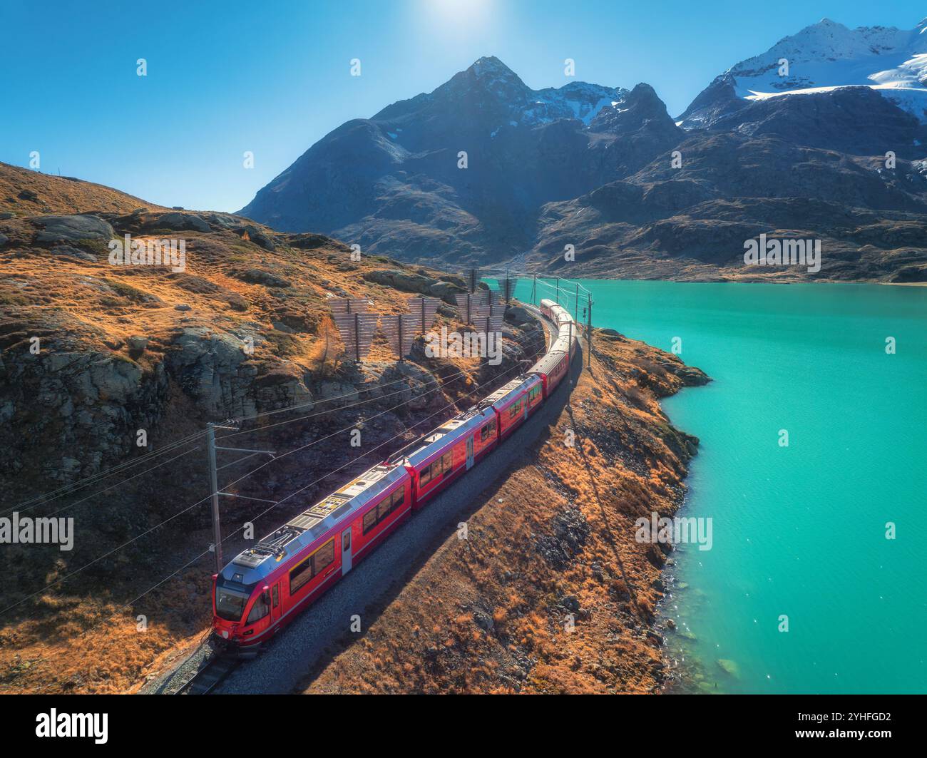 Aerial view of red train near azure mountain lake, snowy rocks Stock ...