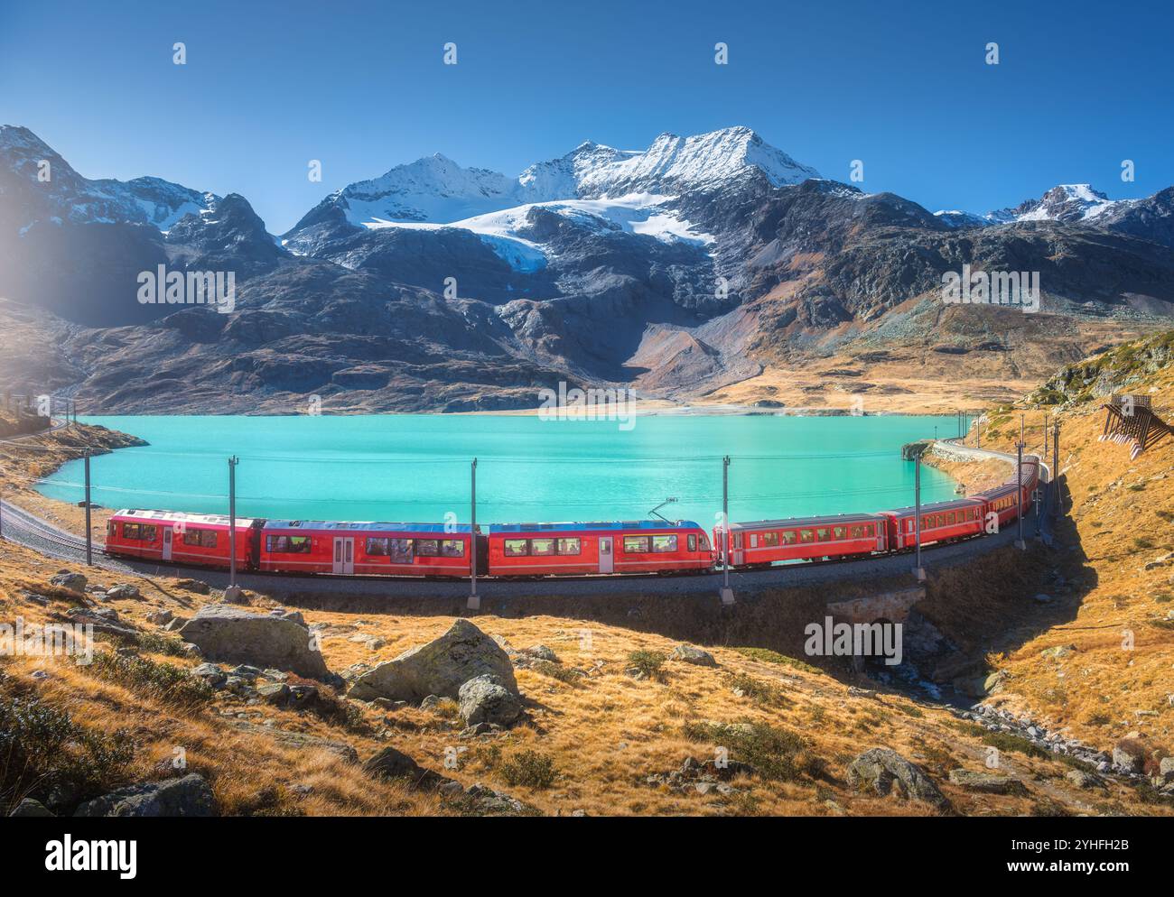 Aerial view of red train near azure mountain lake, snowy rocks Stock ...
