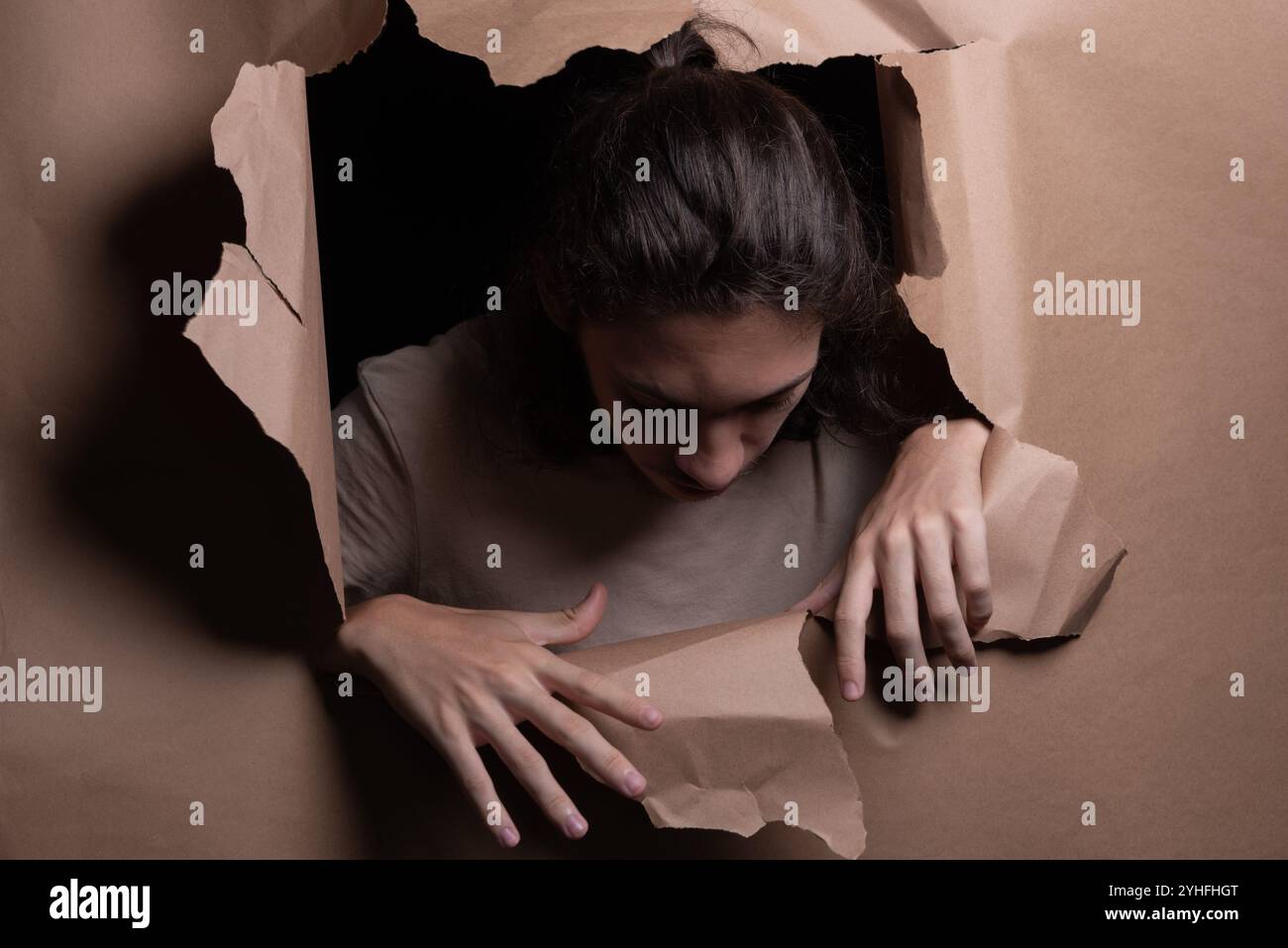 Man face and head sticking out and looking through a hole in brown ...