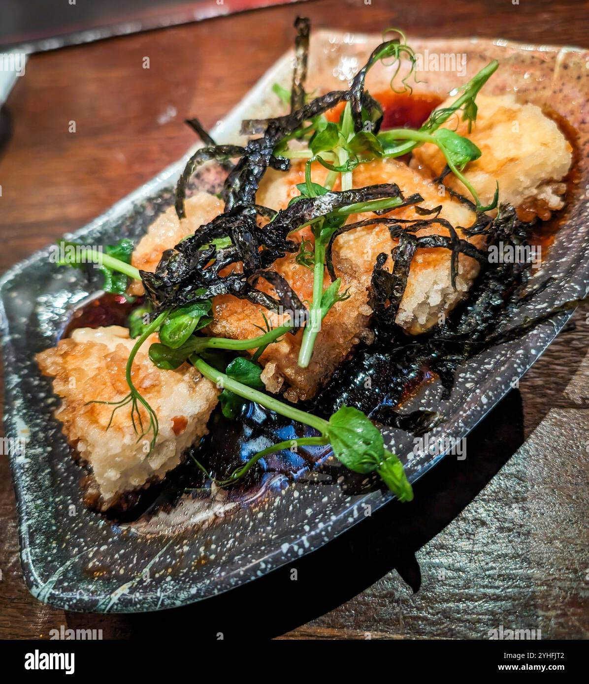 Japanese fried tofu with seaweed on a dark plate on the restaurant ...