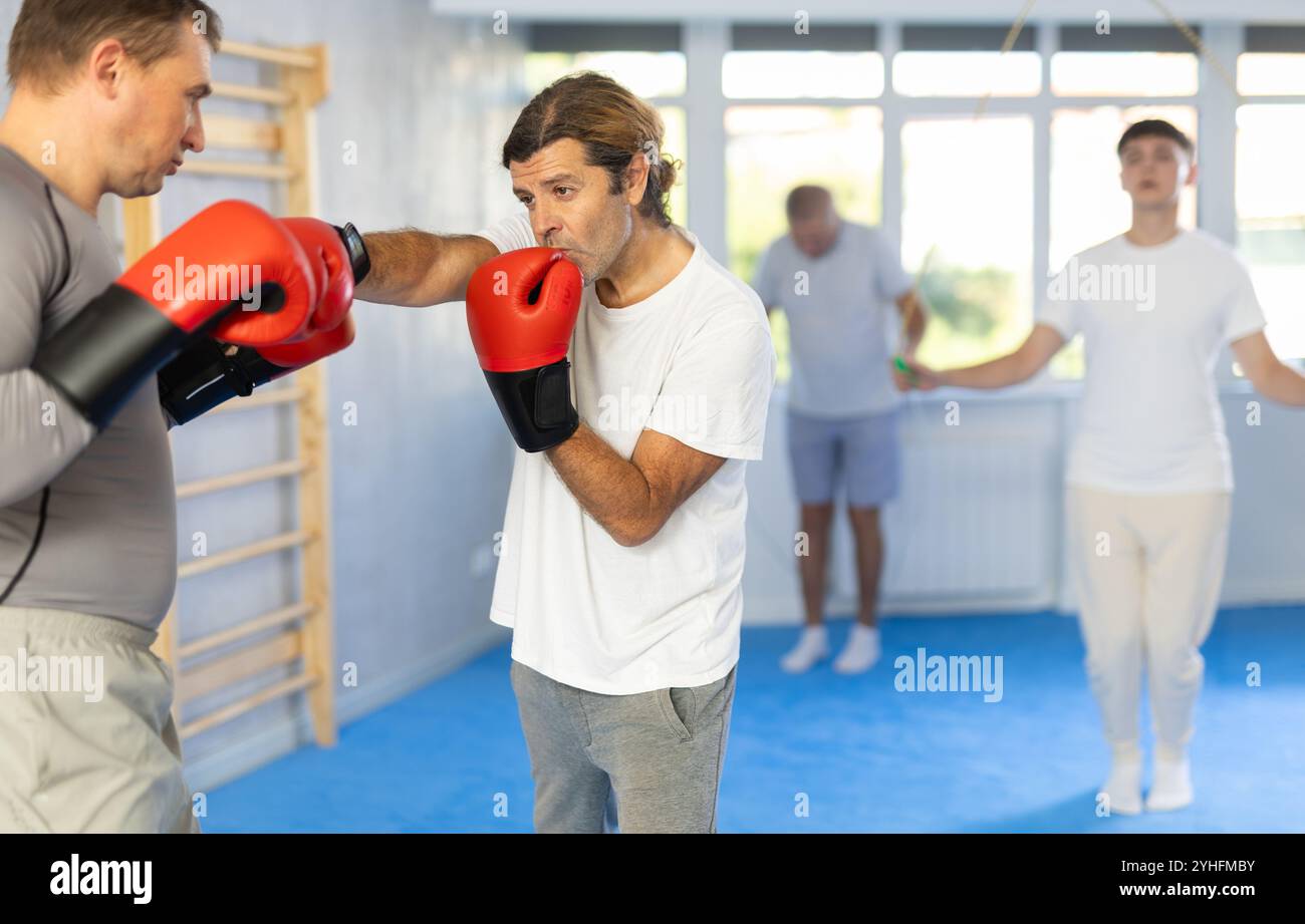 Two men in boxing training perform sparring and one man blocked blow ...
