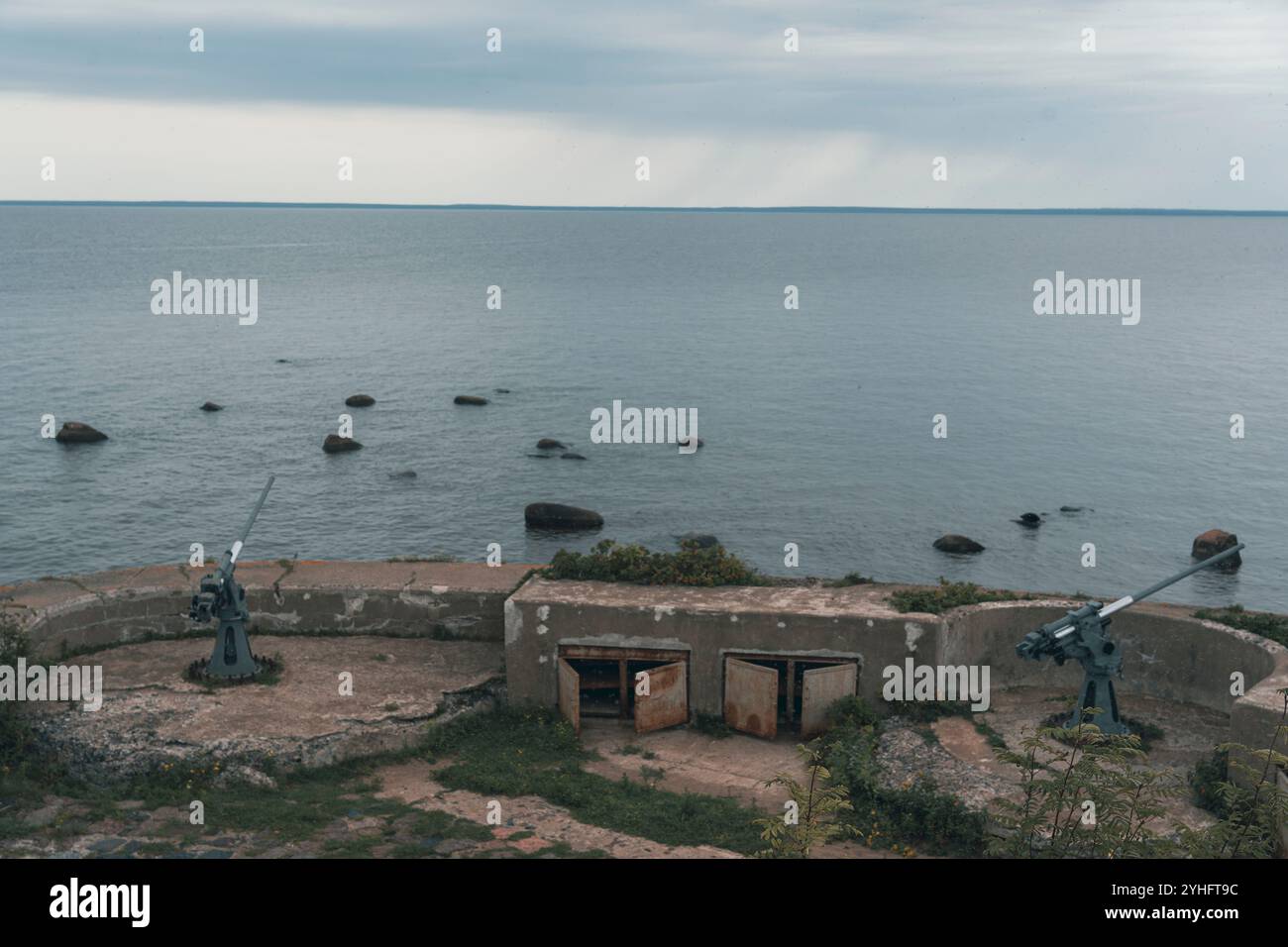 An abandoned coastal artillery bunker with cannons overlooks a calm sea ...