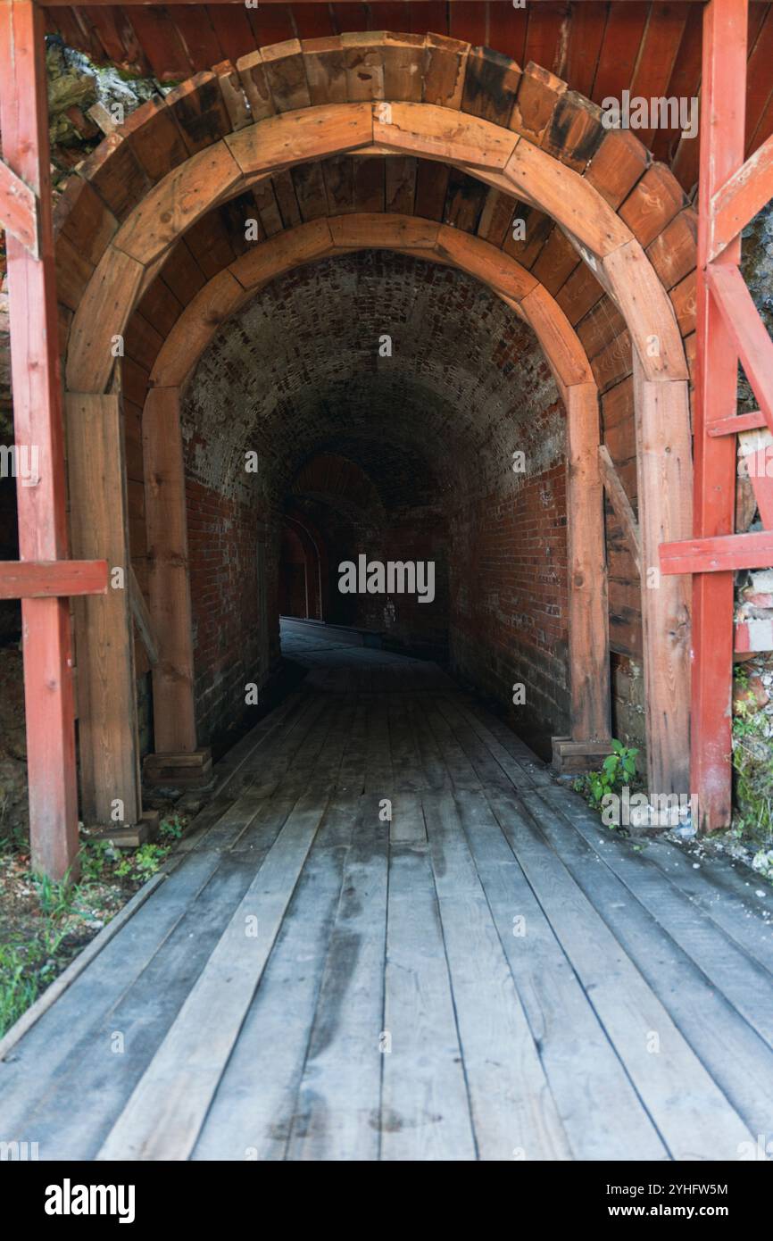 An arched entrance leading into a dark tunnel constructed with wood and ...