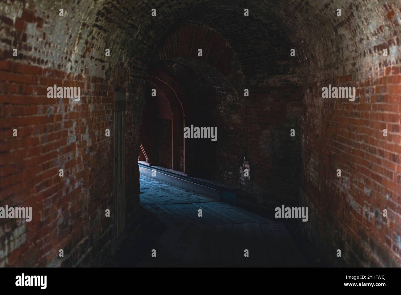 Interior of a dark, narrow brick tunnel with an arched ceiling inside a ...