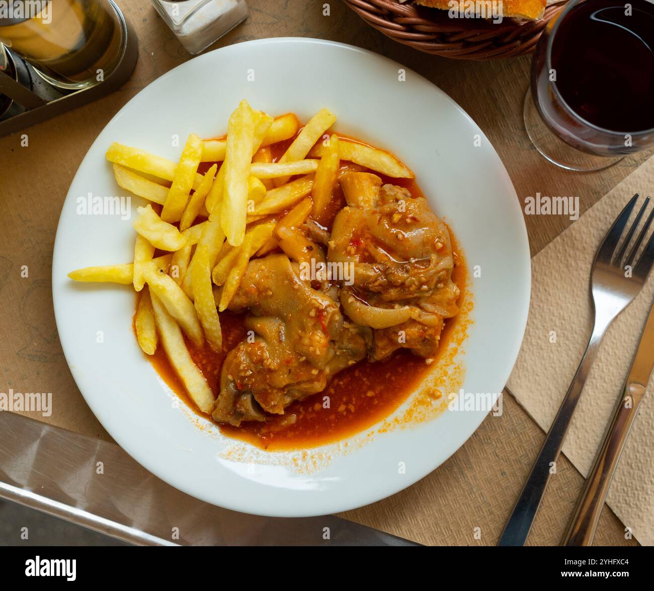Pork trotters stewed in tomato gravy with fries Stock Photo - Alamy