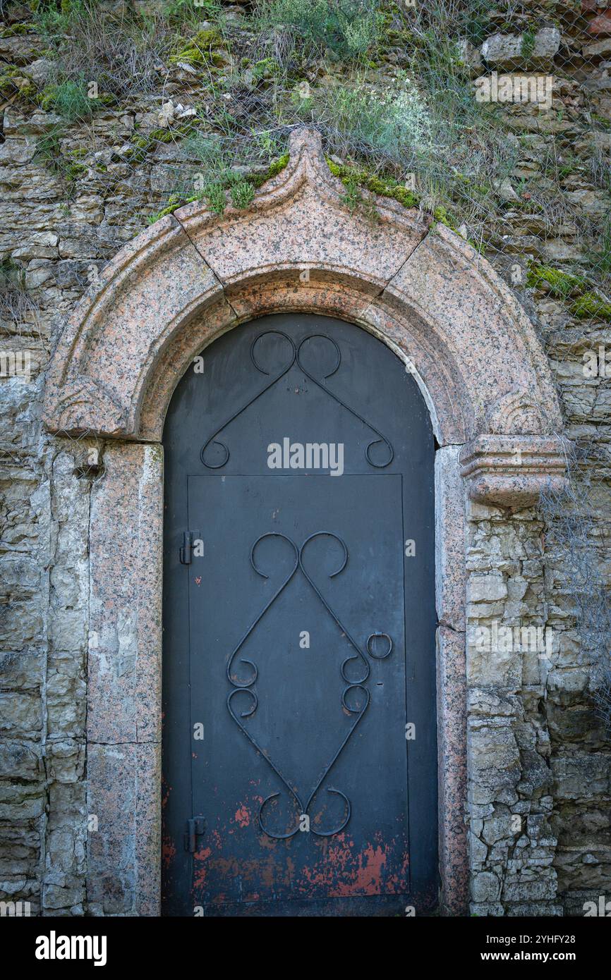 An ancient stone door with an arched opening and forged elements ...