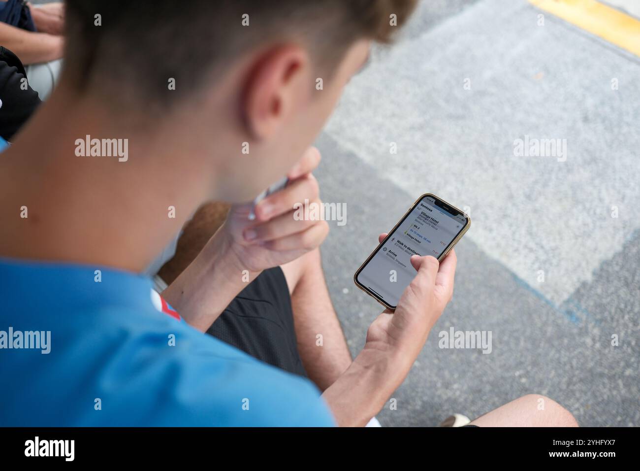 A young adult boy using an iPhone to get directions in Singapore ...