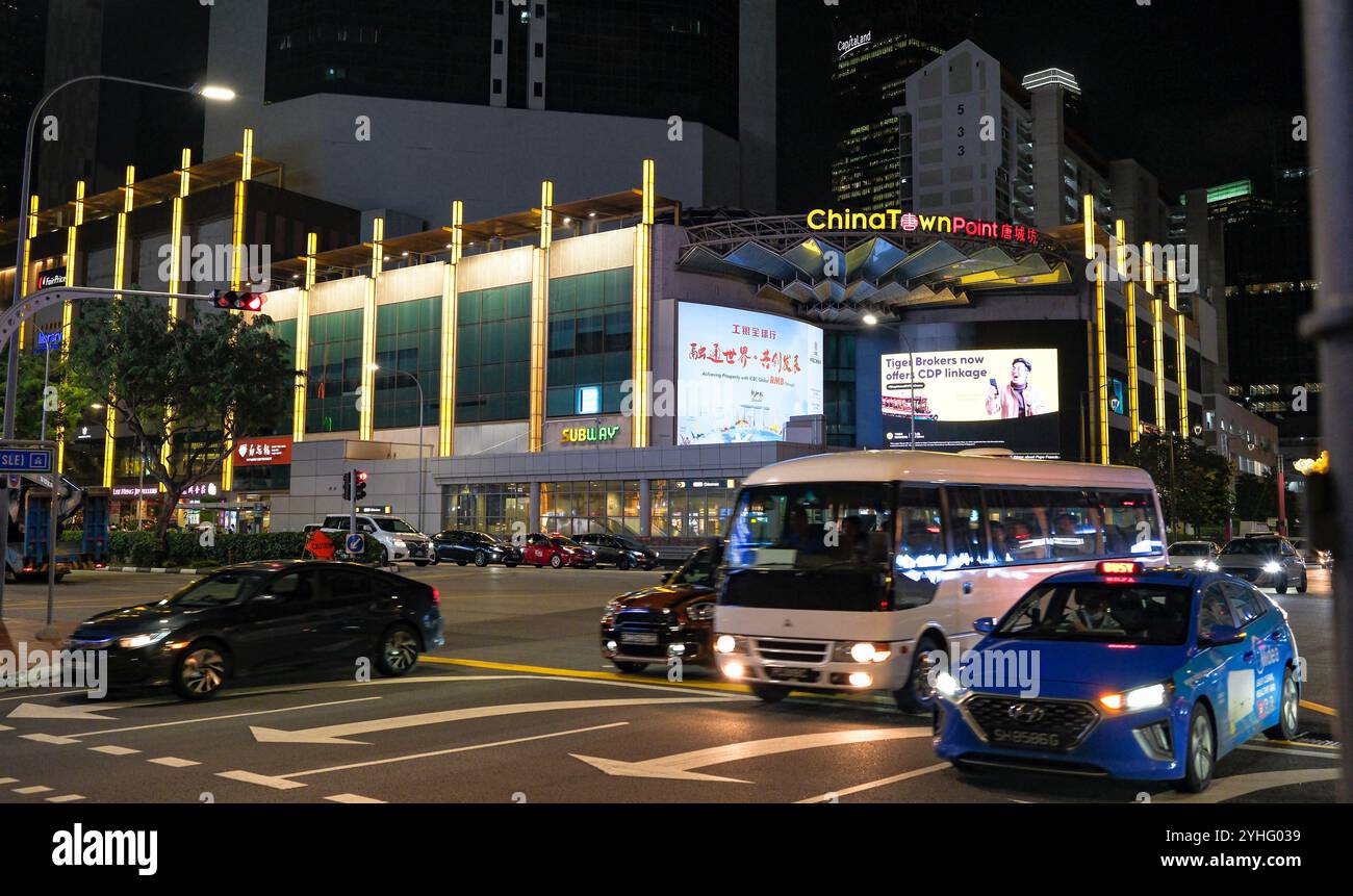 Nightime scene of Chinatown point shopping centre with traffic and road junction in the ...