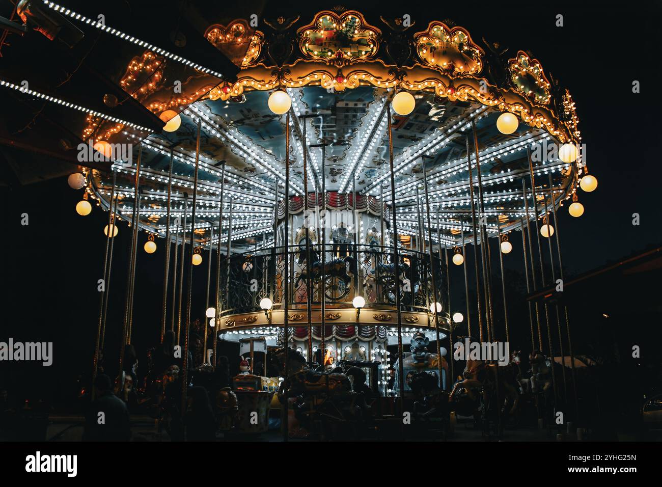 A brightly lit carousel at night, with glowing lights illuminating the ...
