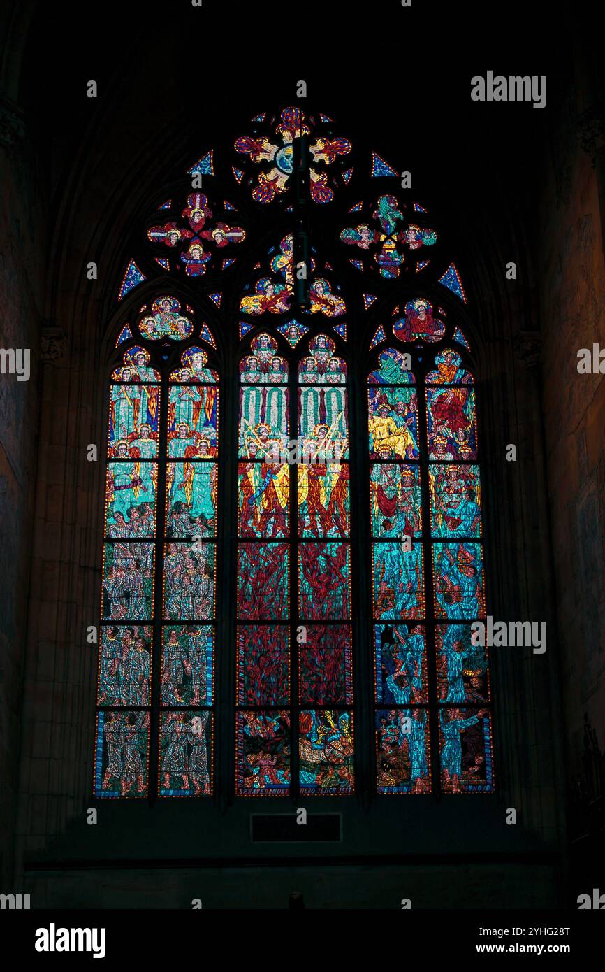 A vibrant stained glass window in St. Vitus Cathedral in Prague, depicting biblical scenes with ...