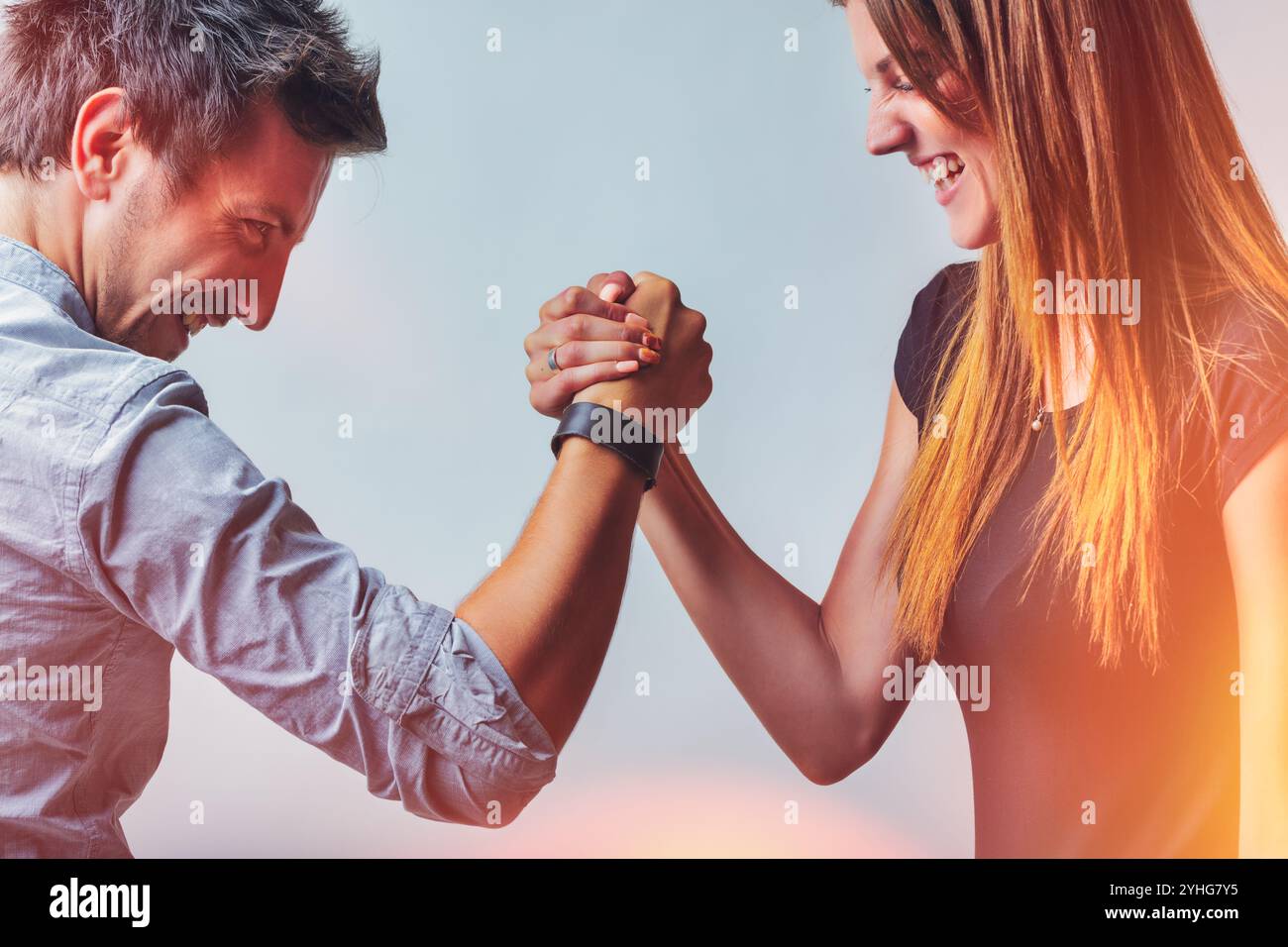 oung man and woman clasp hands in a playful arm-wrestling stance. Their ...