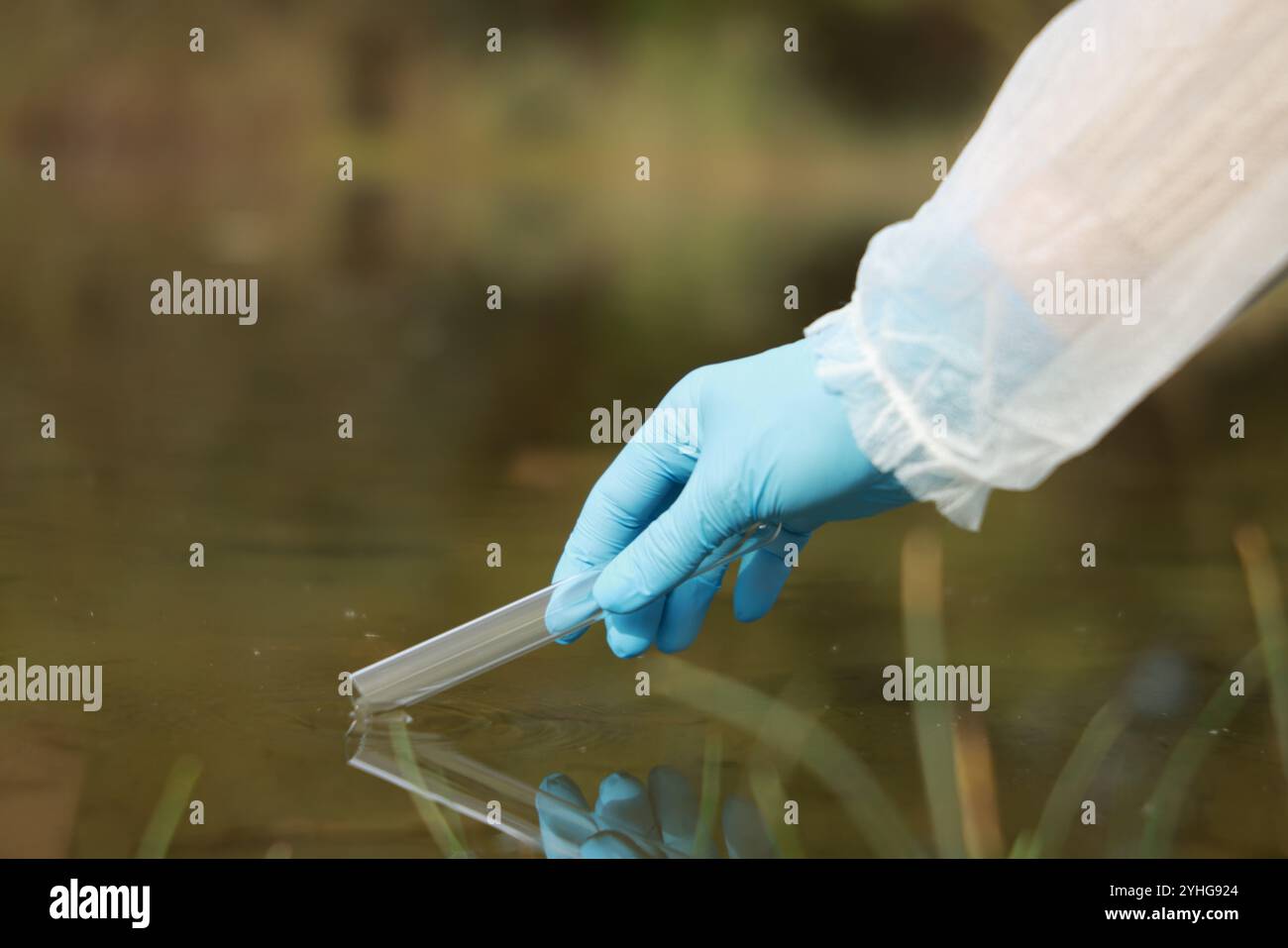 Examination of water quality. Researcher taking water sample from lake ...