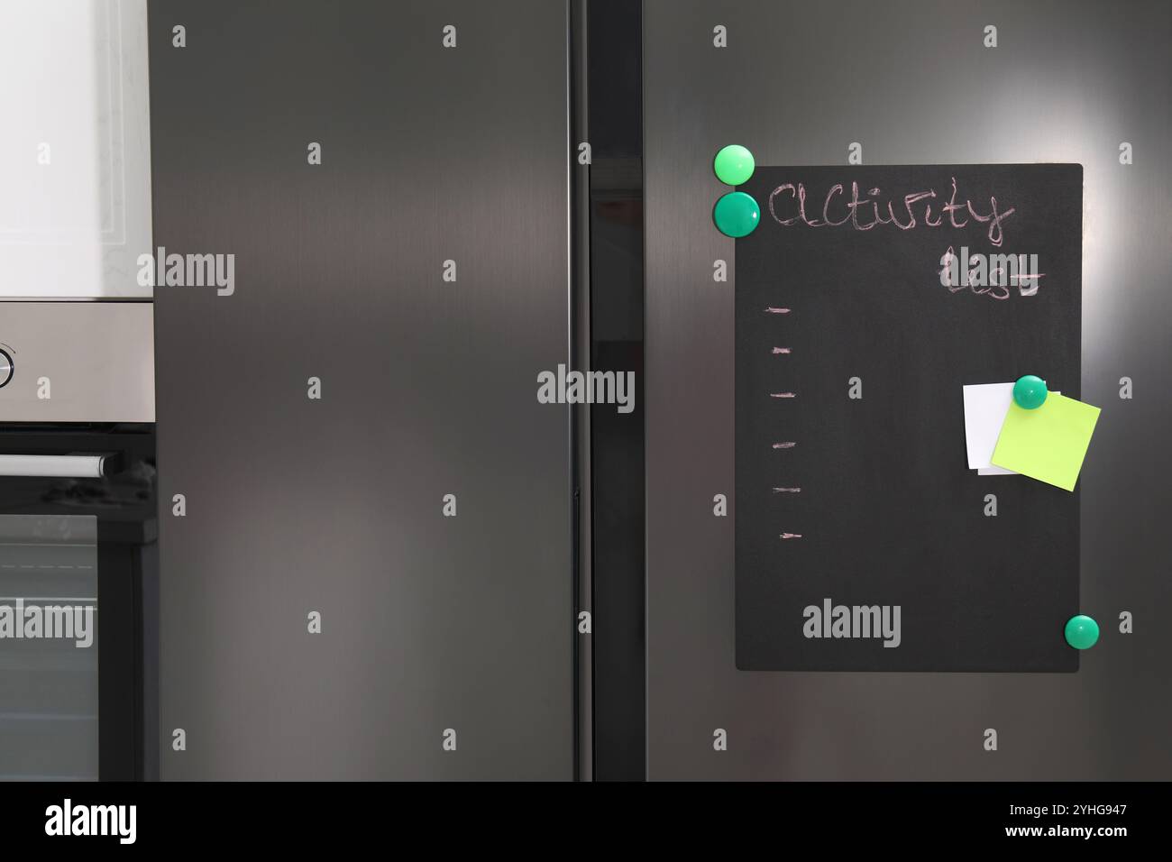 Magnetic board with activity list and notes on refrigerator in kitchen ...