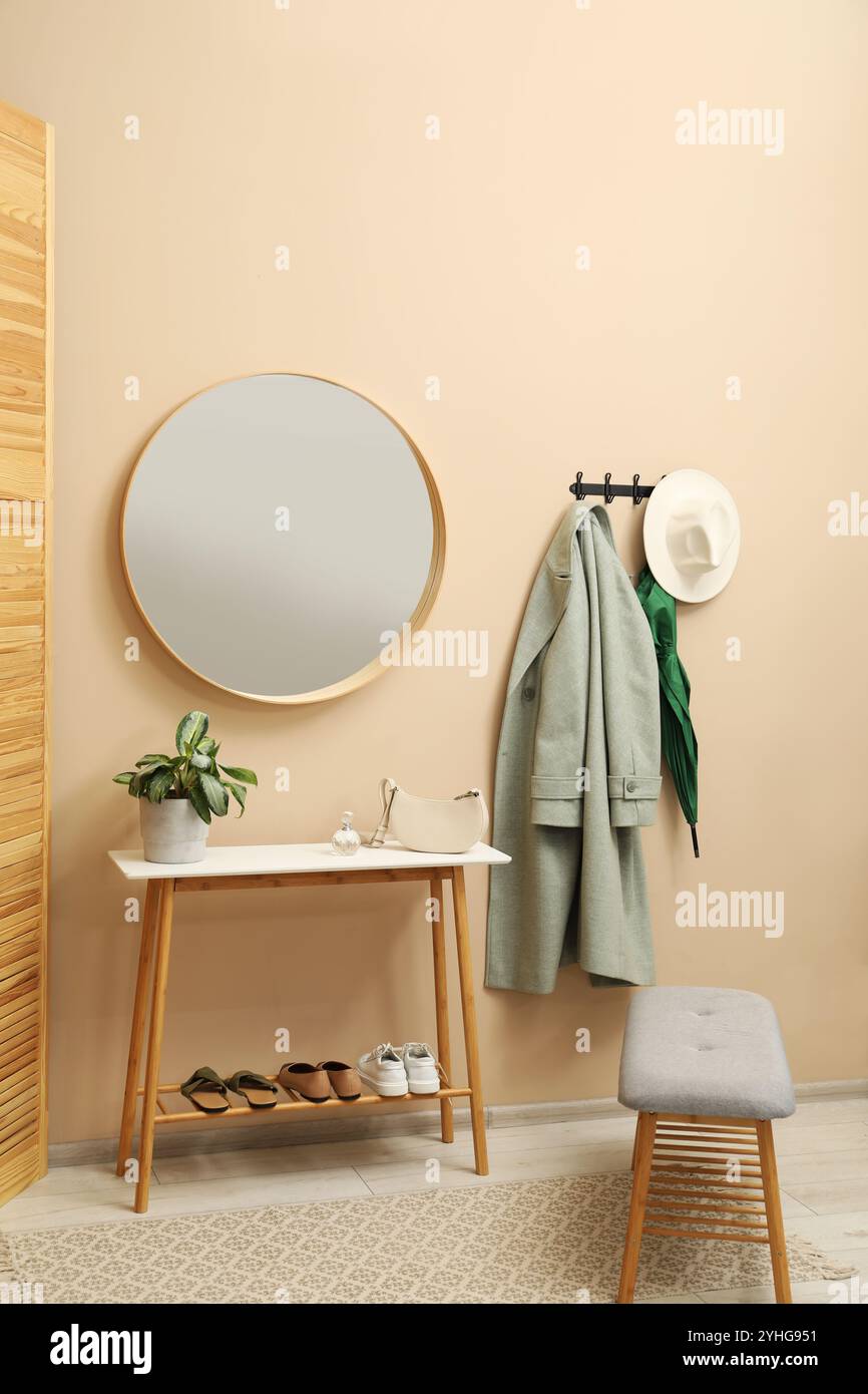 Coat rack with clothes, mirror and shoe storage benches in hallway ...