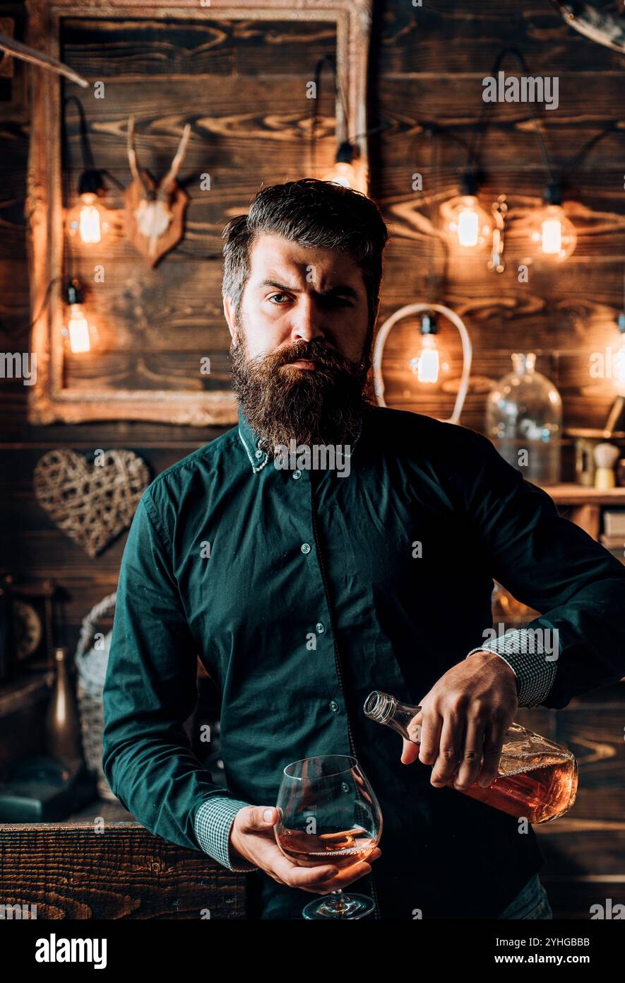 Bearded man sitting at bar. Attractive man with glass of whiskey in his ...