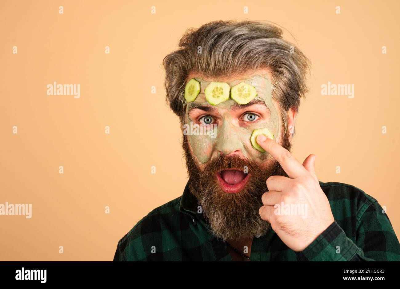 Funny male model with clay mask and cucumber slices on face. Spa ...