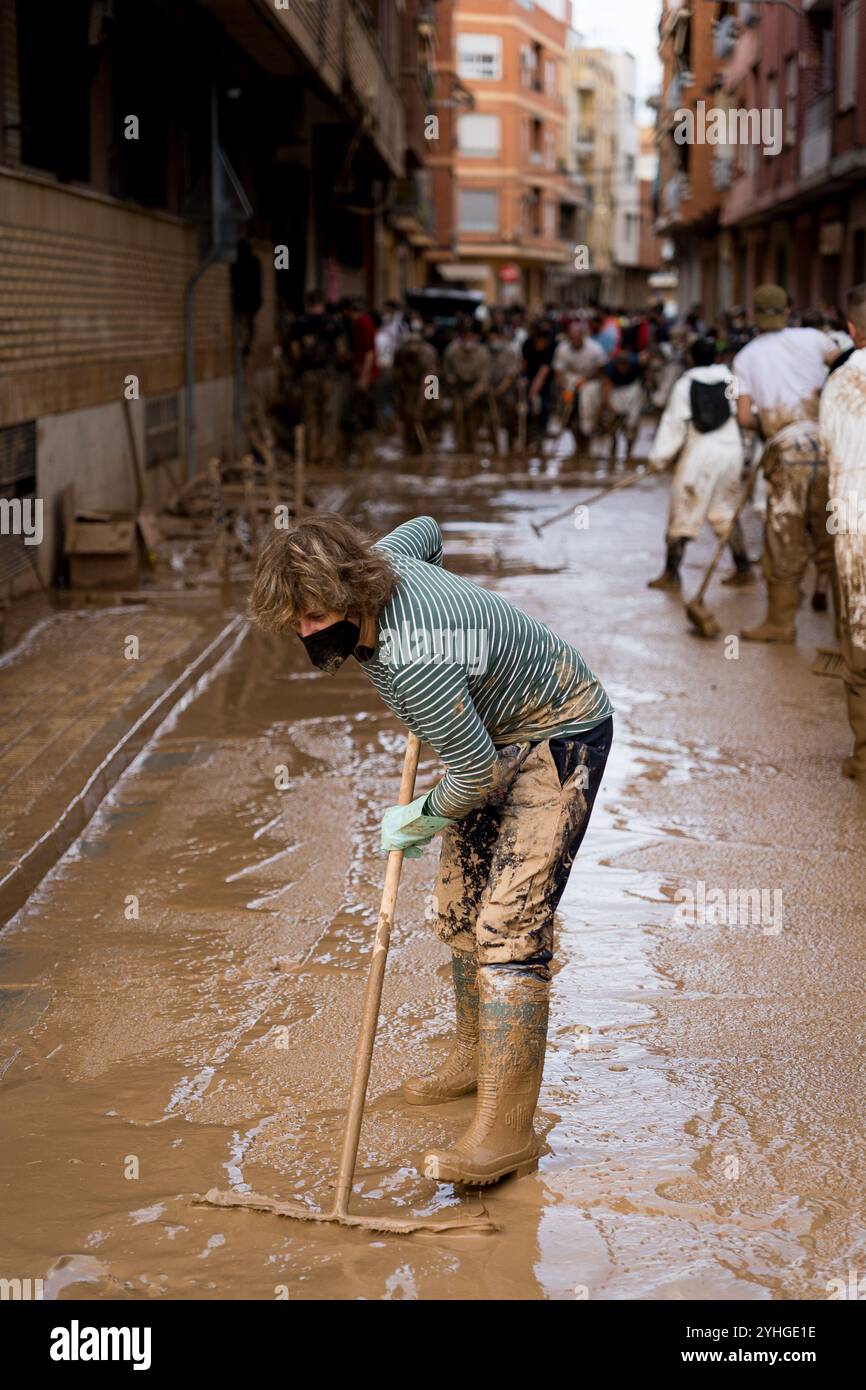 Volunteers are seen manually cleaning the street from the mud with ...