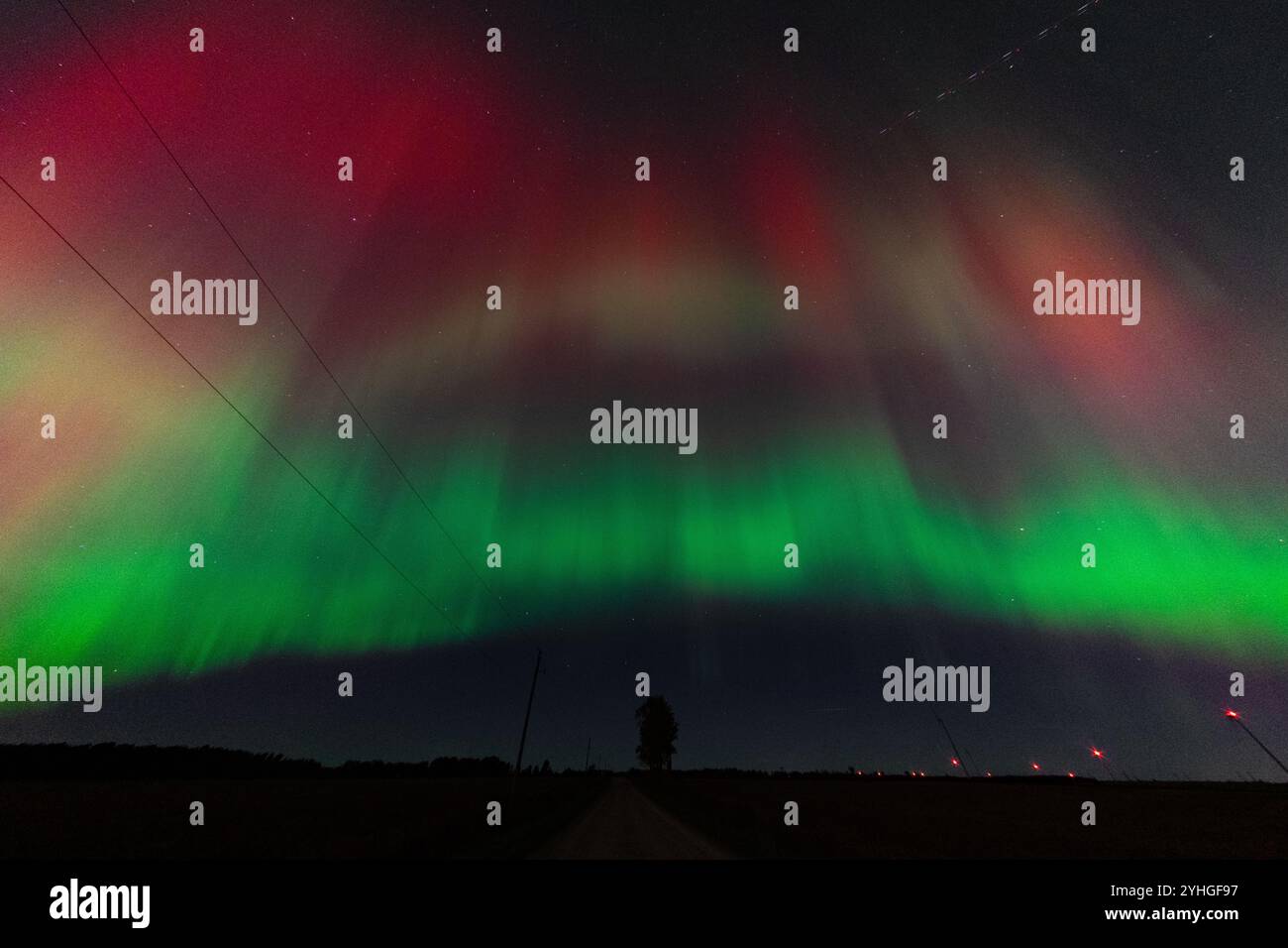 The aurora borealis lights up the night sky above a country road, with ...