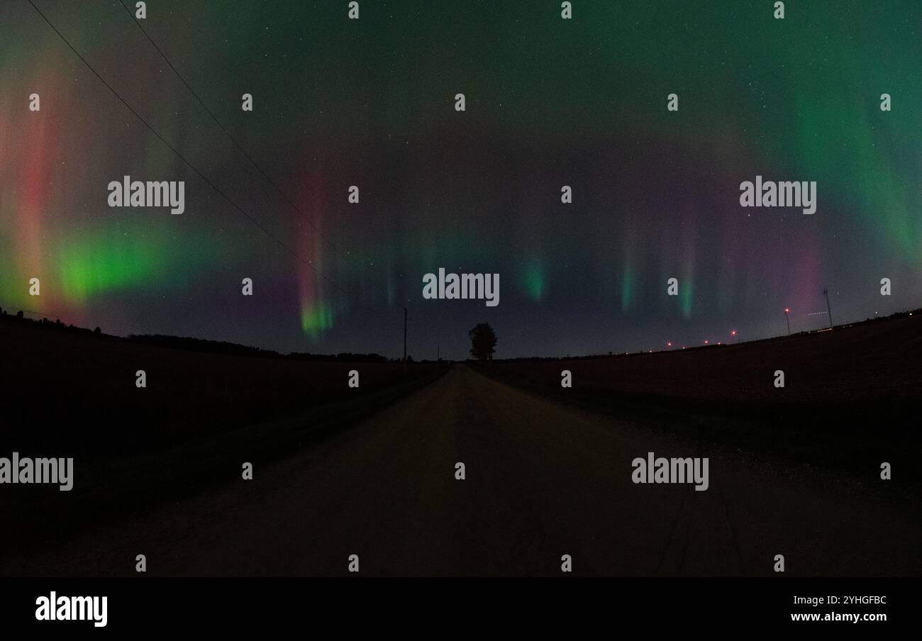 The aurora borealis dances across the night sky above a quiet country ...