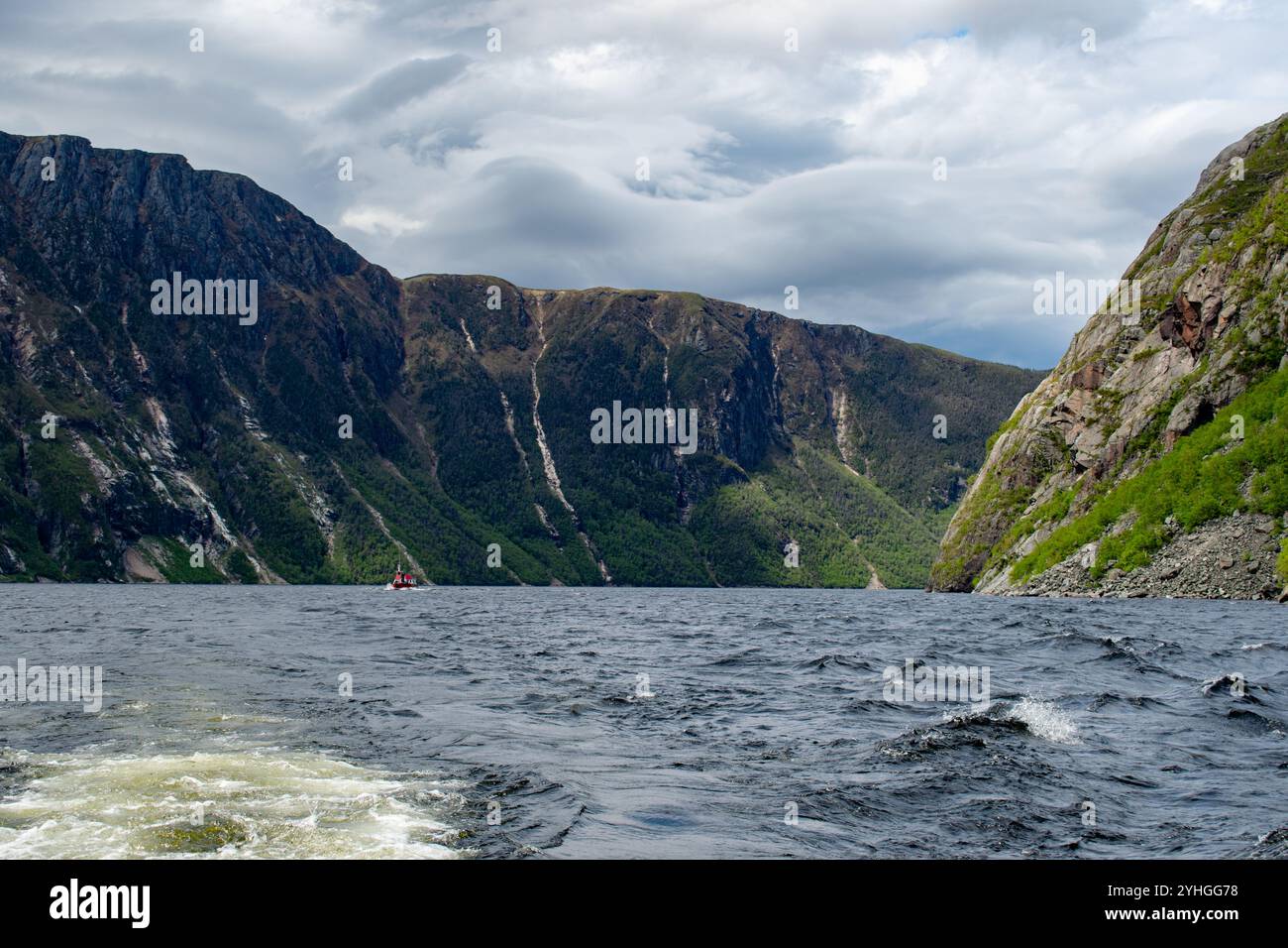 The towering cliffs of Western Brook Pond dwarf a tiny ship below ...
