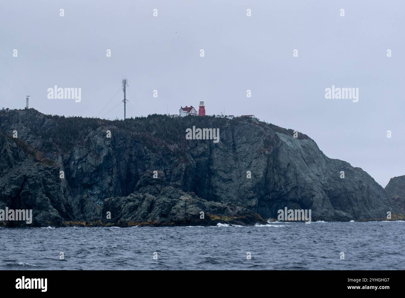 A red lighthouse stands proudly on towering cliffs, with a ...