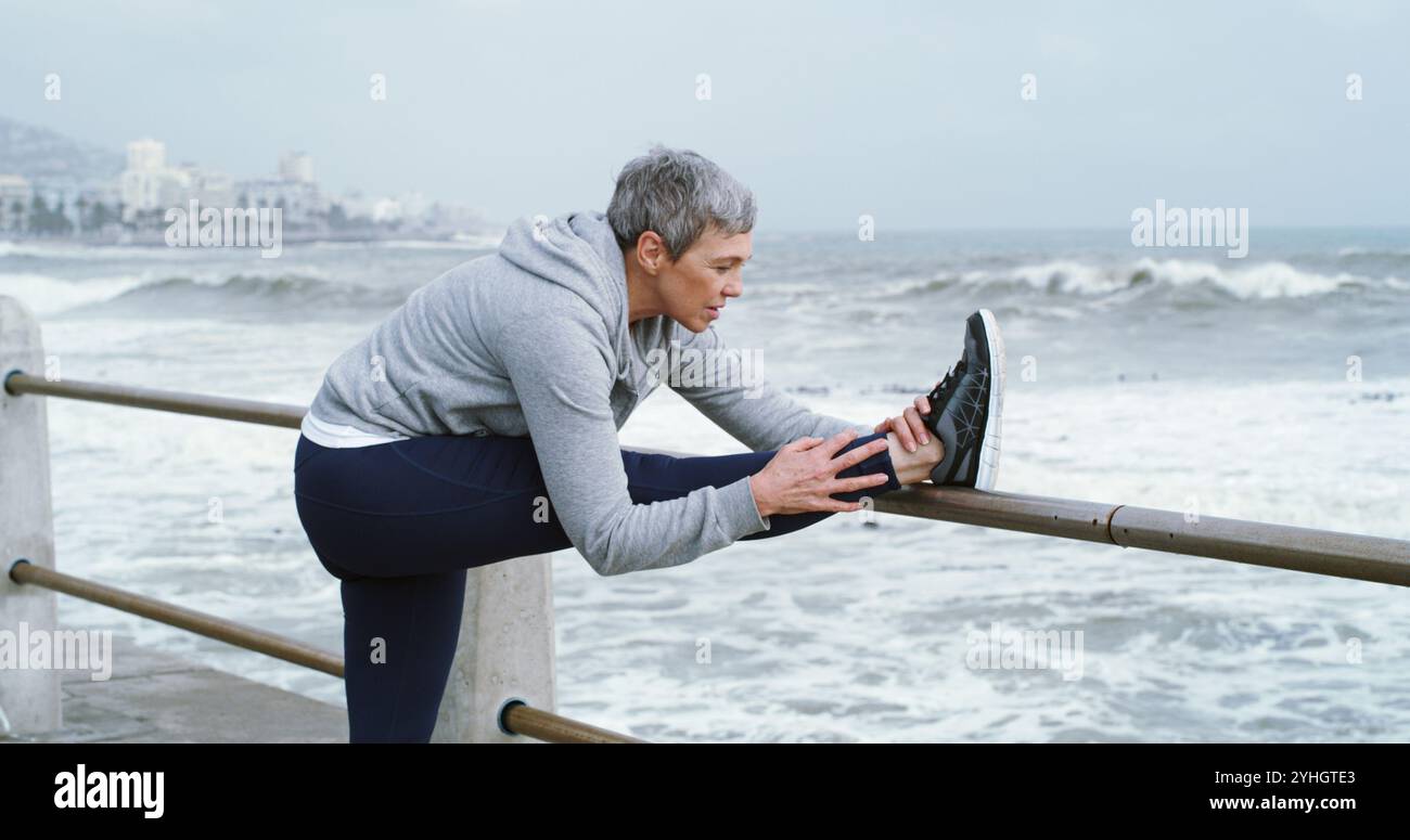 Mature person, stretching legs and fitness at ocean with peace ...