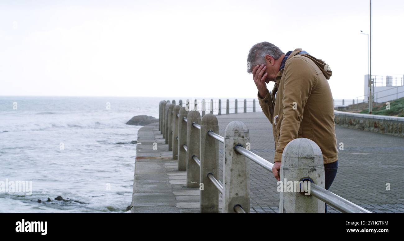 Senior man, thinking and sad by sea promenade with headache, stress and ...