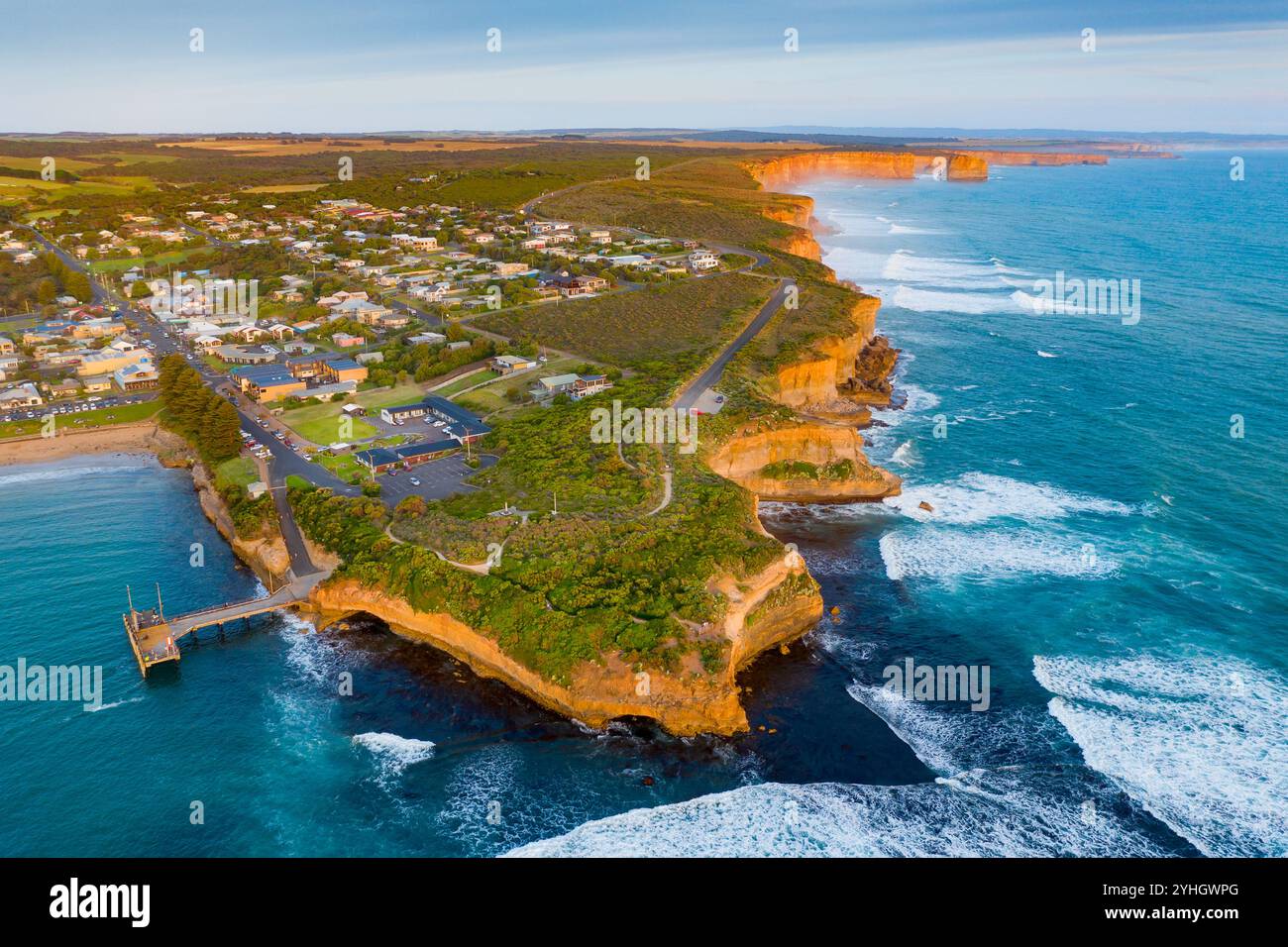 Aerial view of a coastal town nestles behind a small bay along a rugged ...