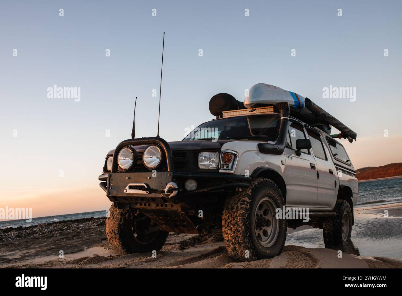 Kitted out 4WD adventuring on the beach at dusk, over a sand bank and ...