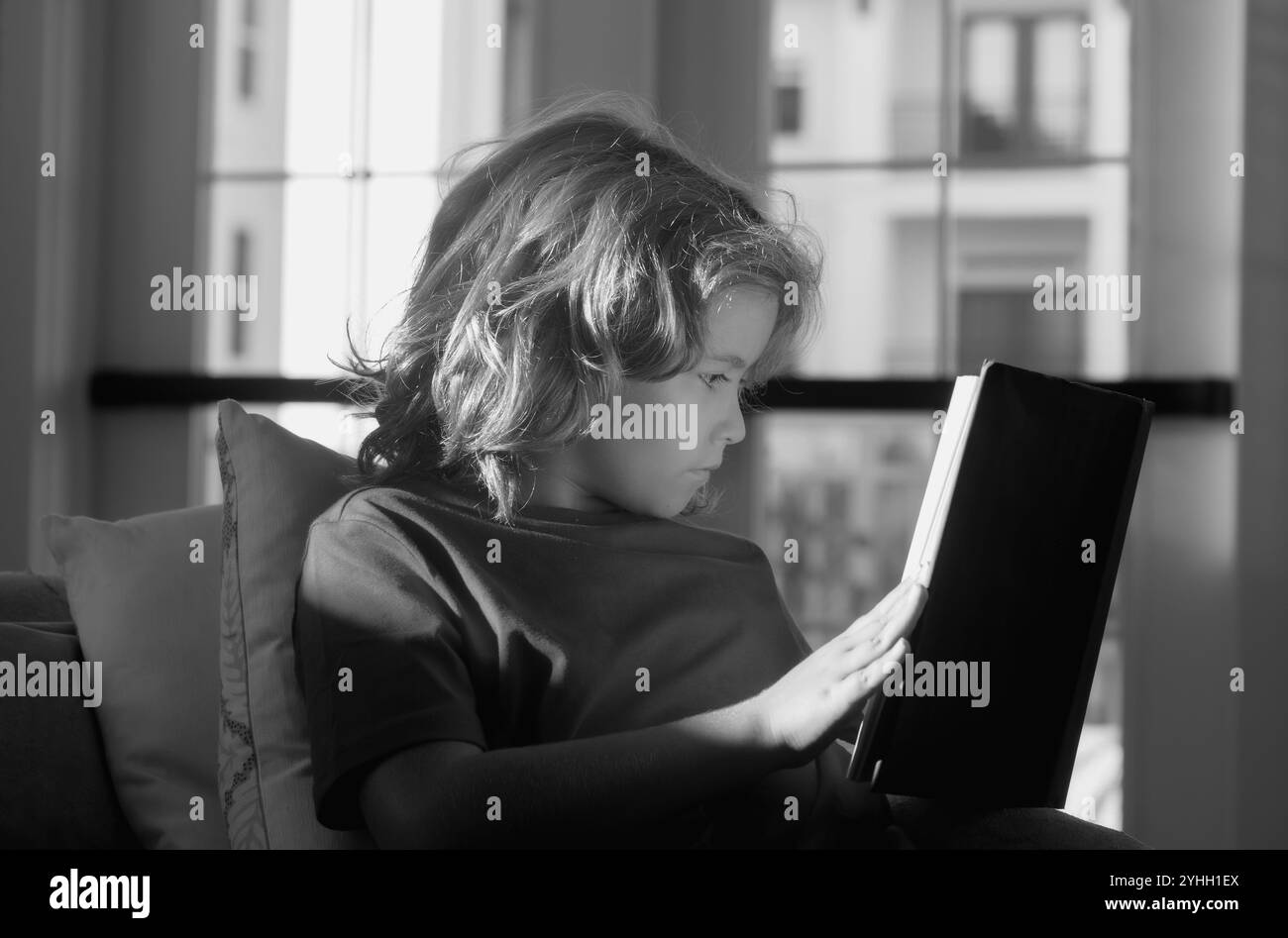 Child reading book at home. Little boy sitting on couch in living room ...