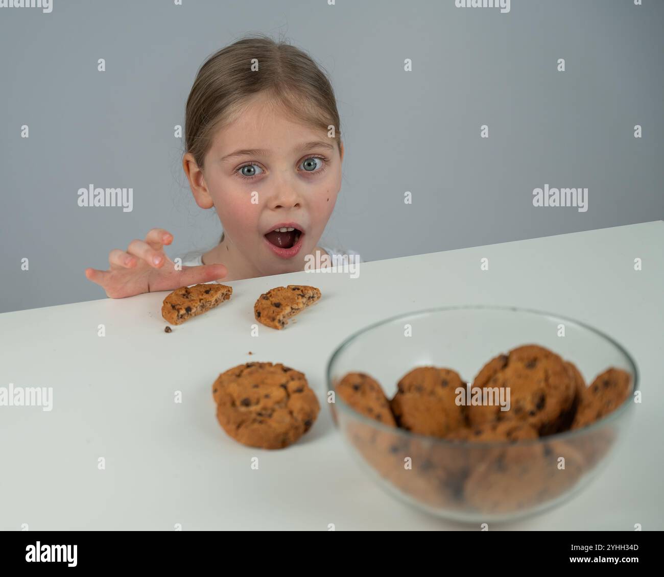 A little girl tries to steal cookies from the table Stock Photo - Alamy