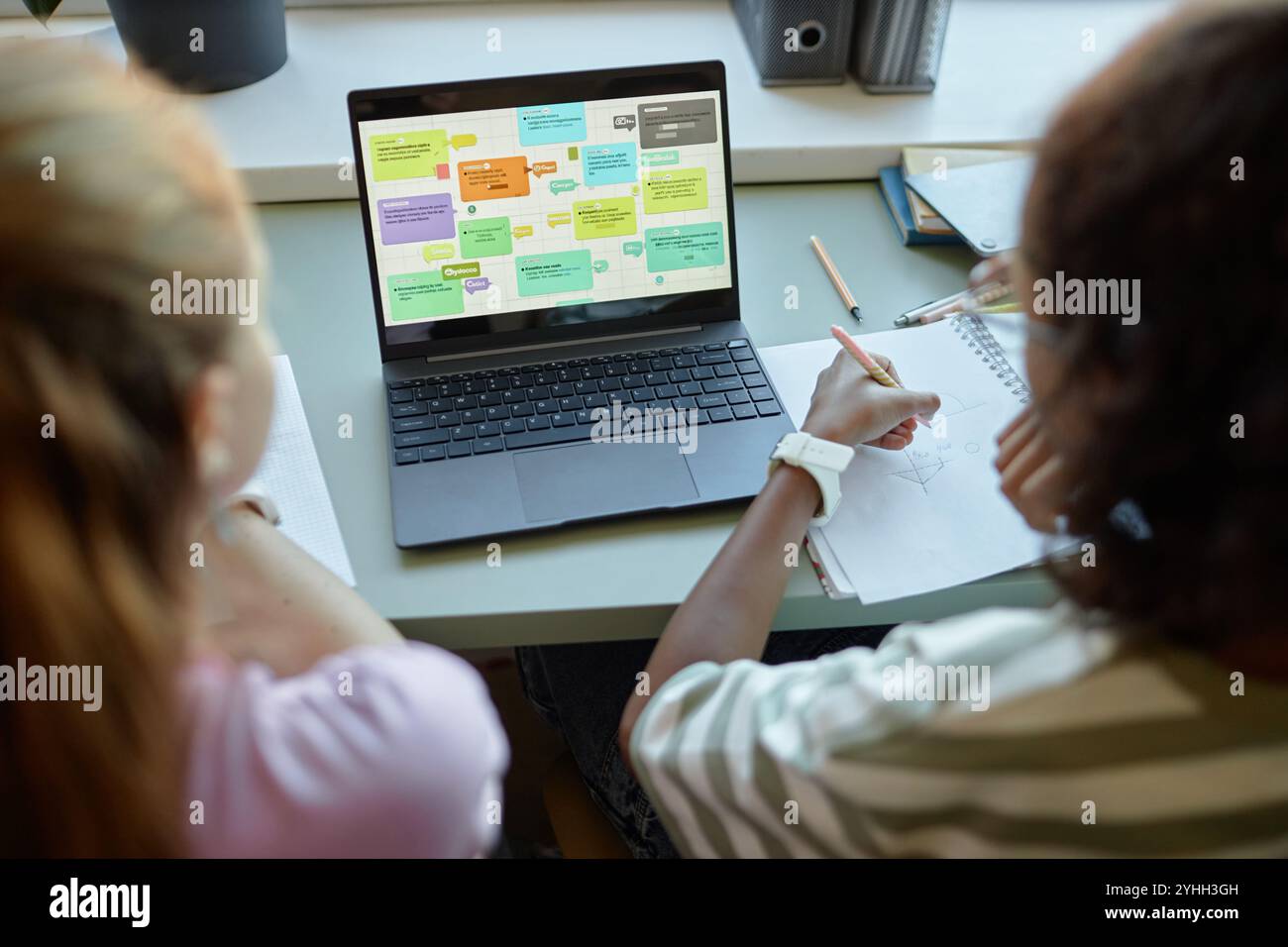 Over shoulder view of two girls using computer together in school ...