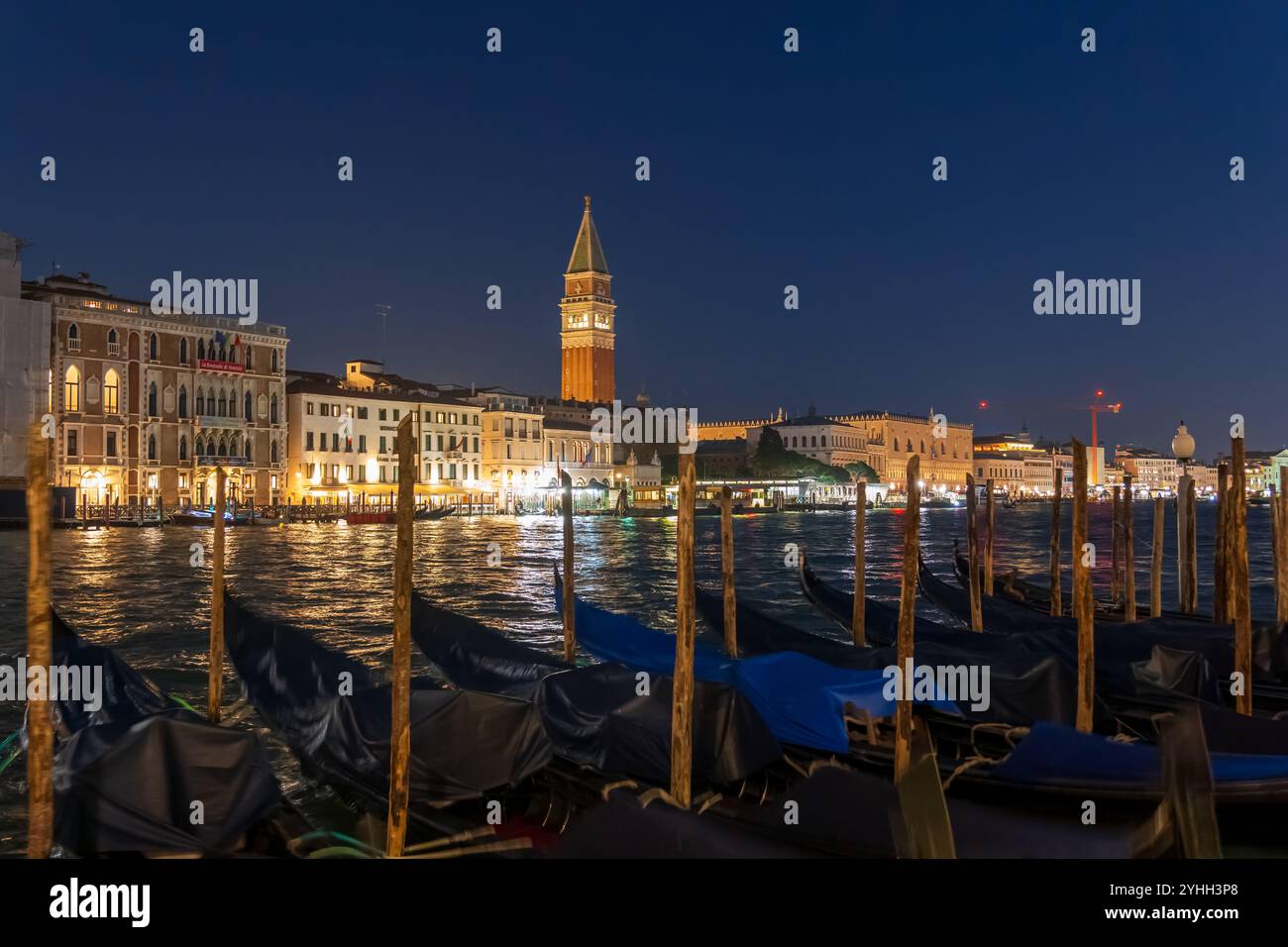 City skyline of Venice at night in Italy. Traditional gondolas boats ...