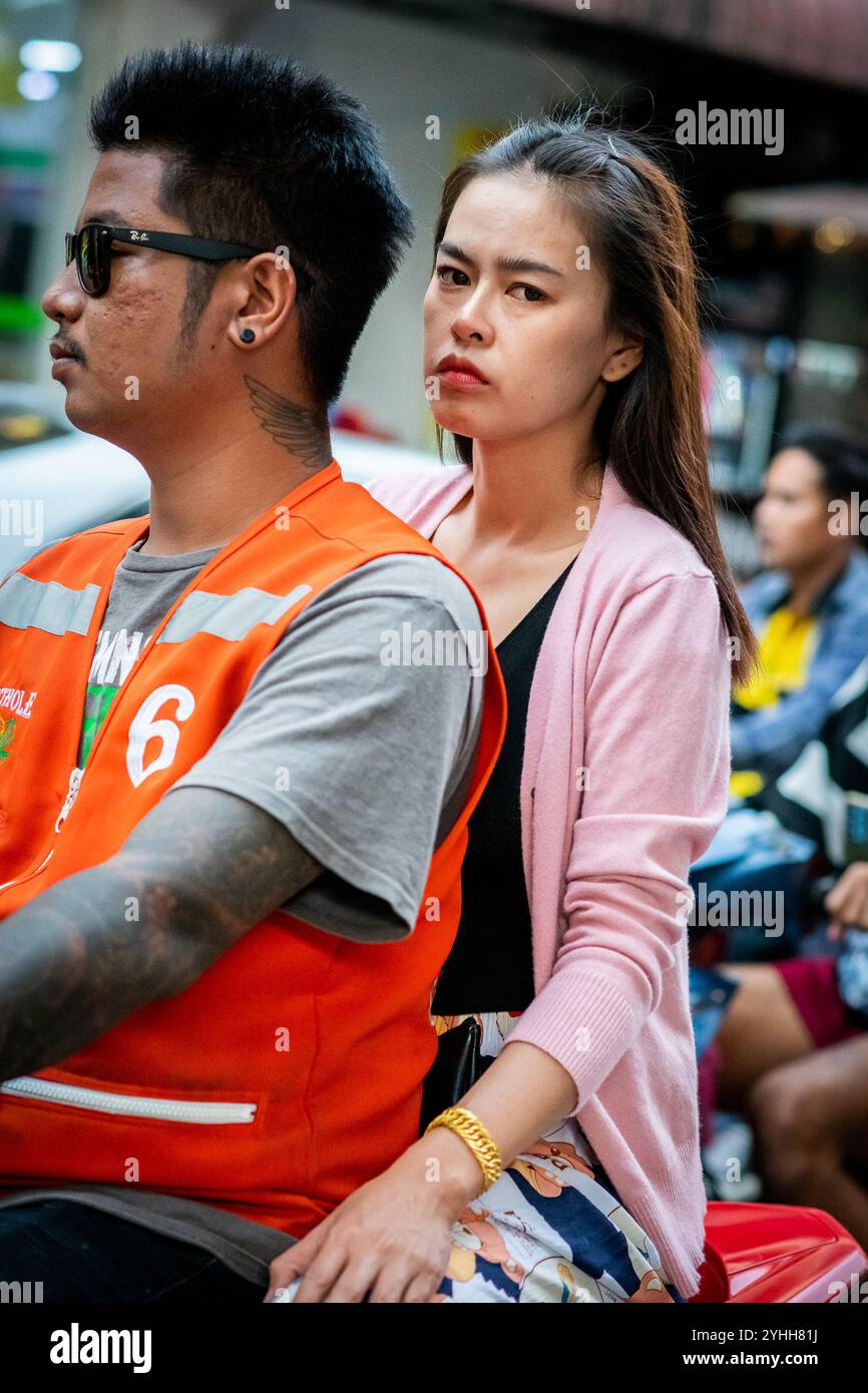 A beautiful young Thai lady rides on the back of a motorbike taxi along ...
