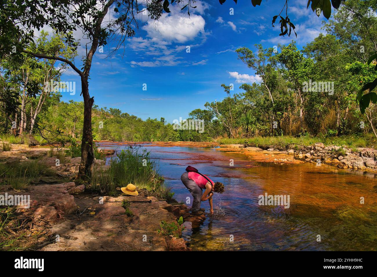 A woman refreshes herself in a shallow river along the Cascades Walk in ...