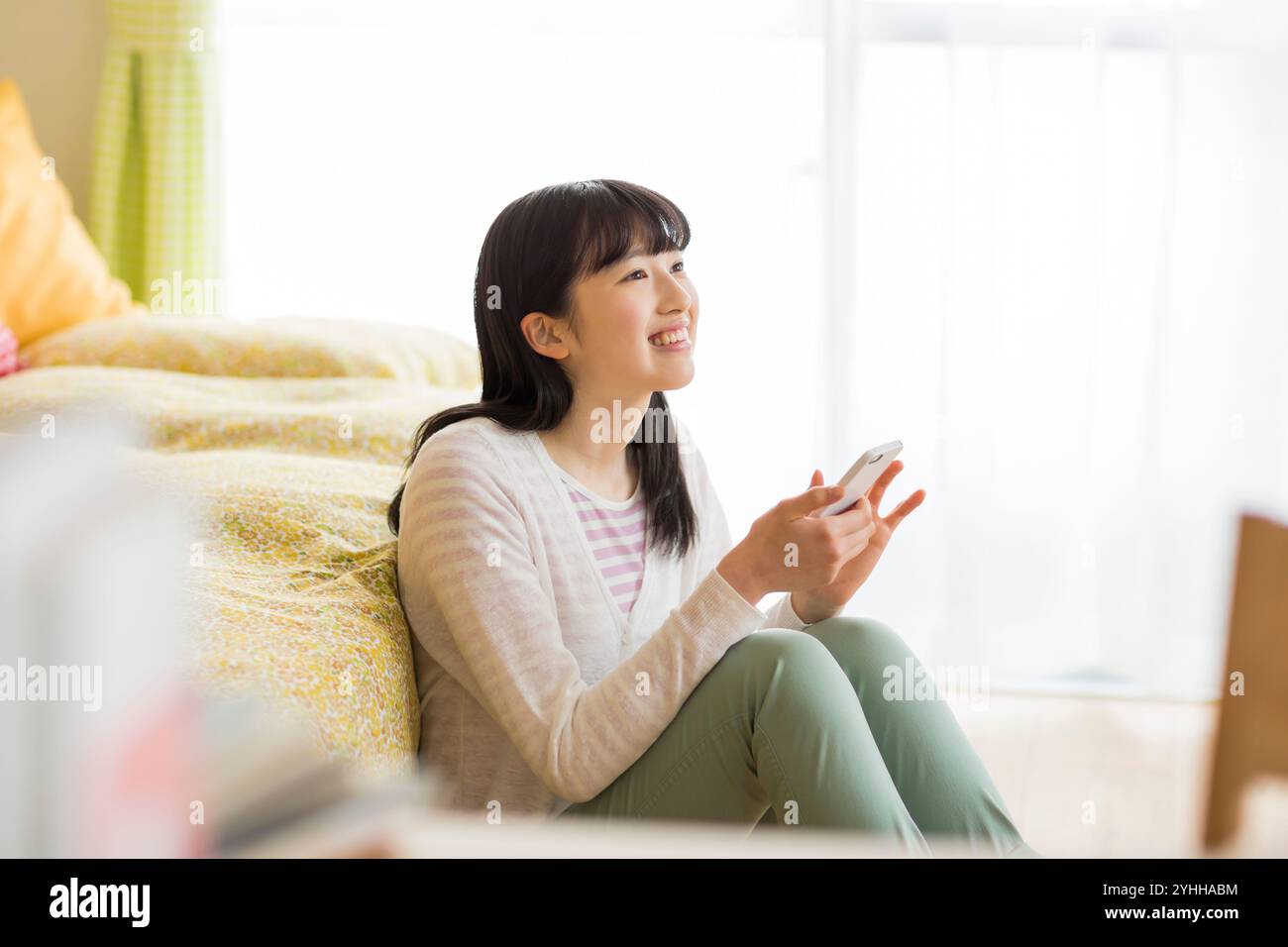 Smiling girl with smartphone in room Stock Photo - Alamy