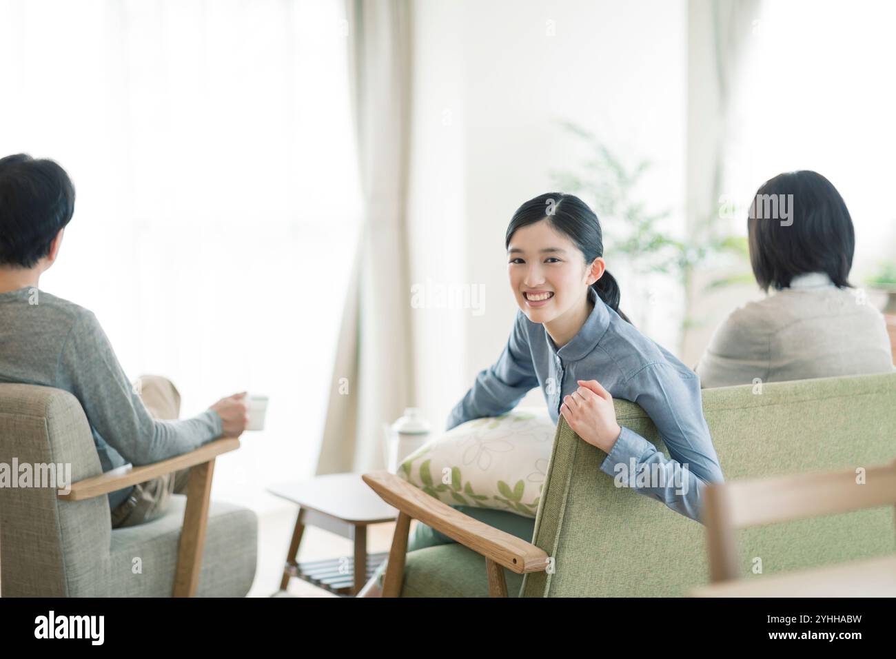 Girl sitting on sofa and turning around Stock Photo - Alamy